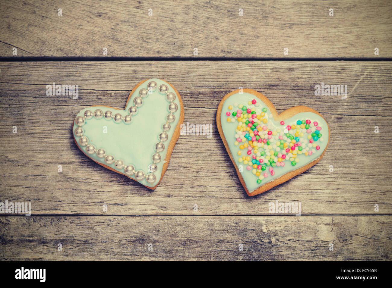 Two baked hearts covered with blue icing. Wooden background, from above ...
