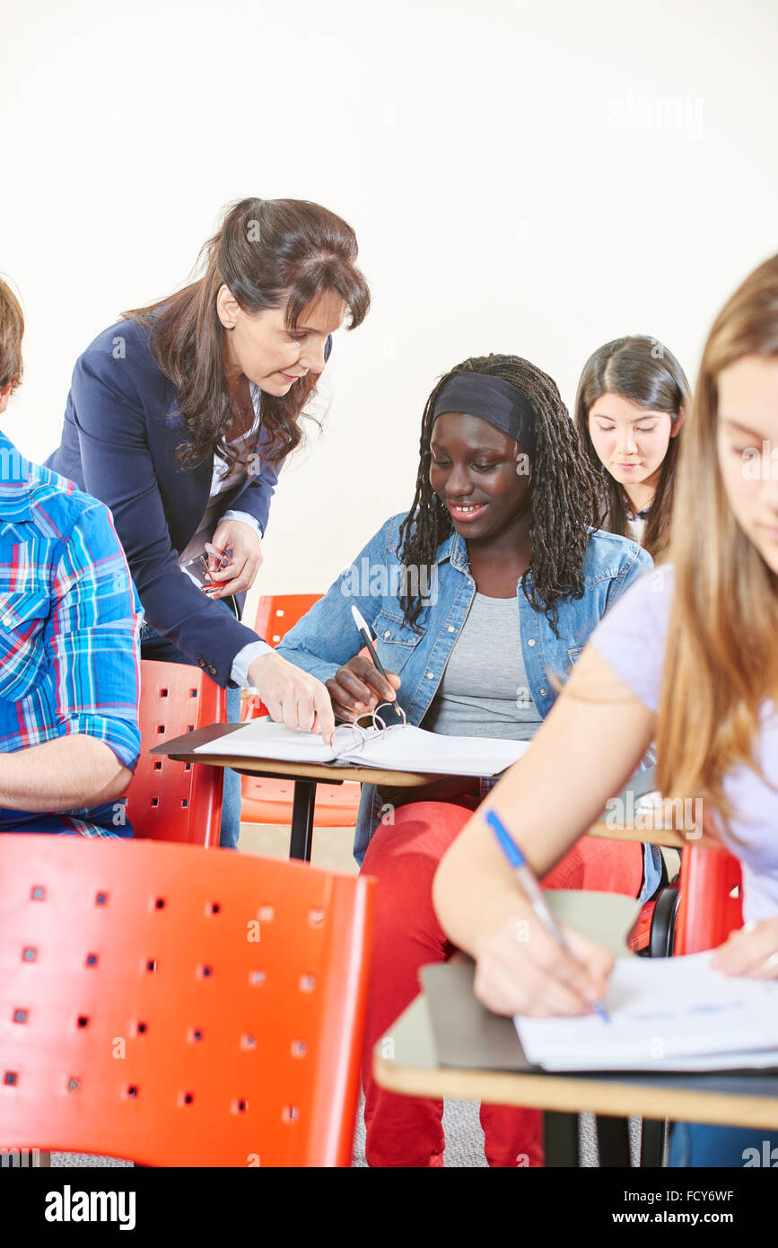 Teacher helping a student in class at school Stock Photo - Alamy