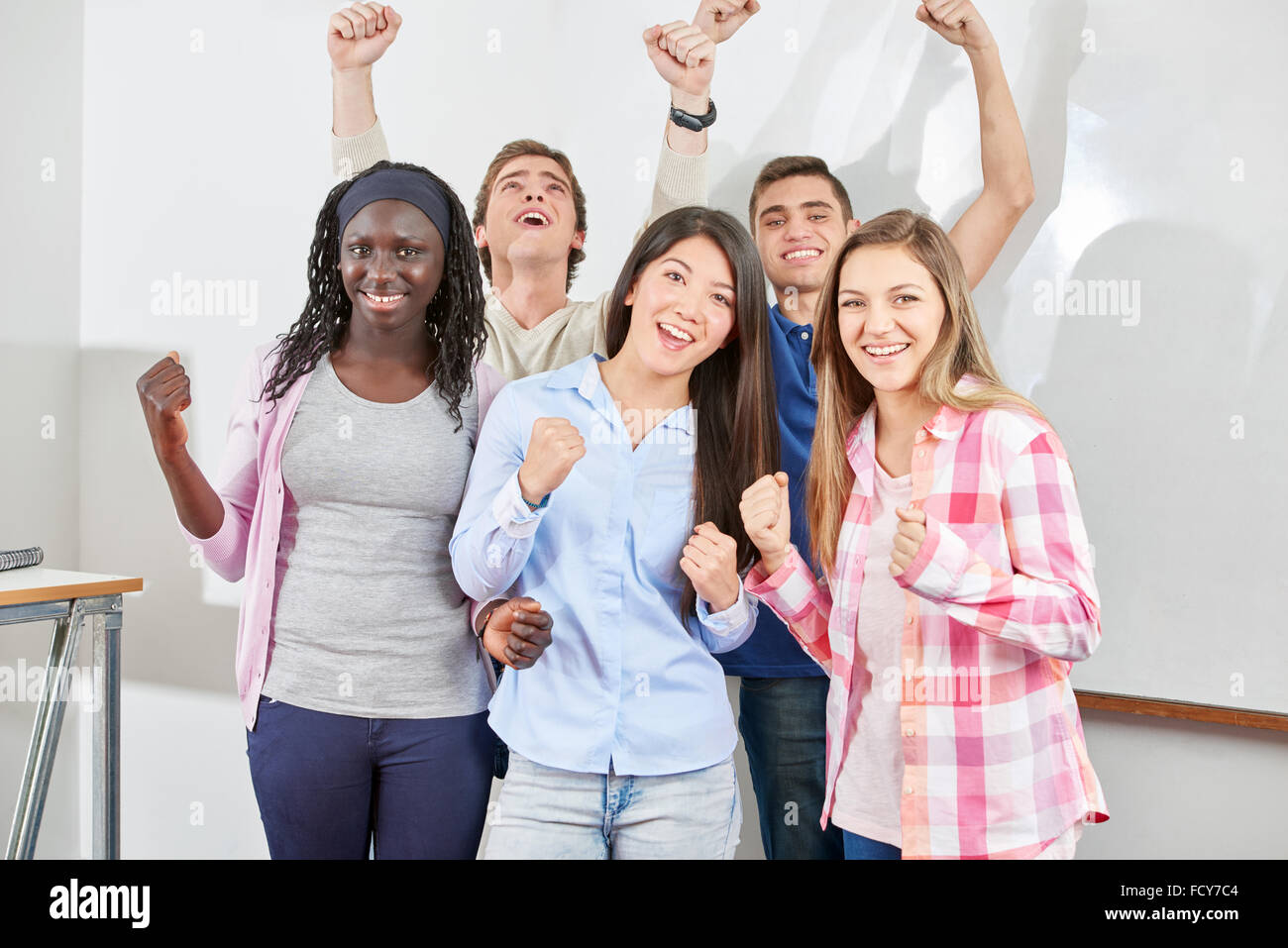 Teenage kids celebrating their success in their high school classroom ...
