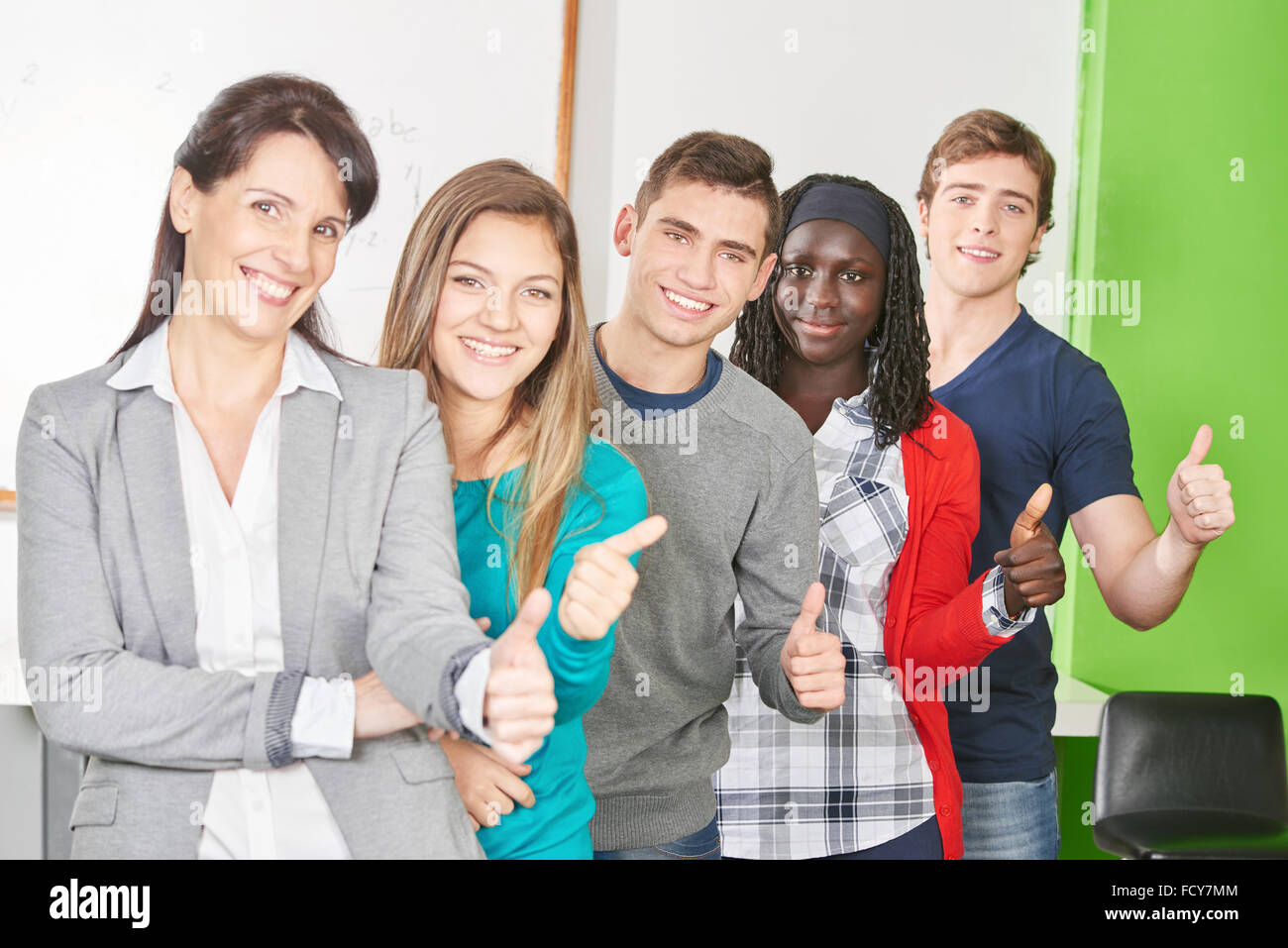 Team of students and teacher hold their thumbs up in high school Stock ...