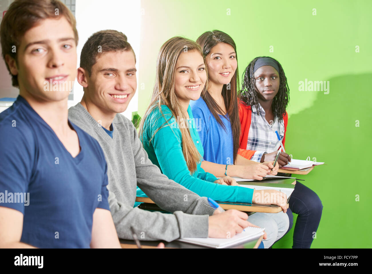 Group of teenage students sit together in their classroom and smile ...