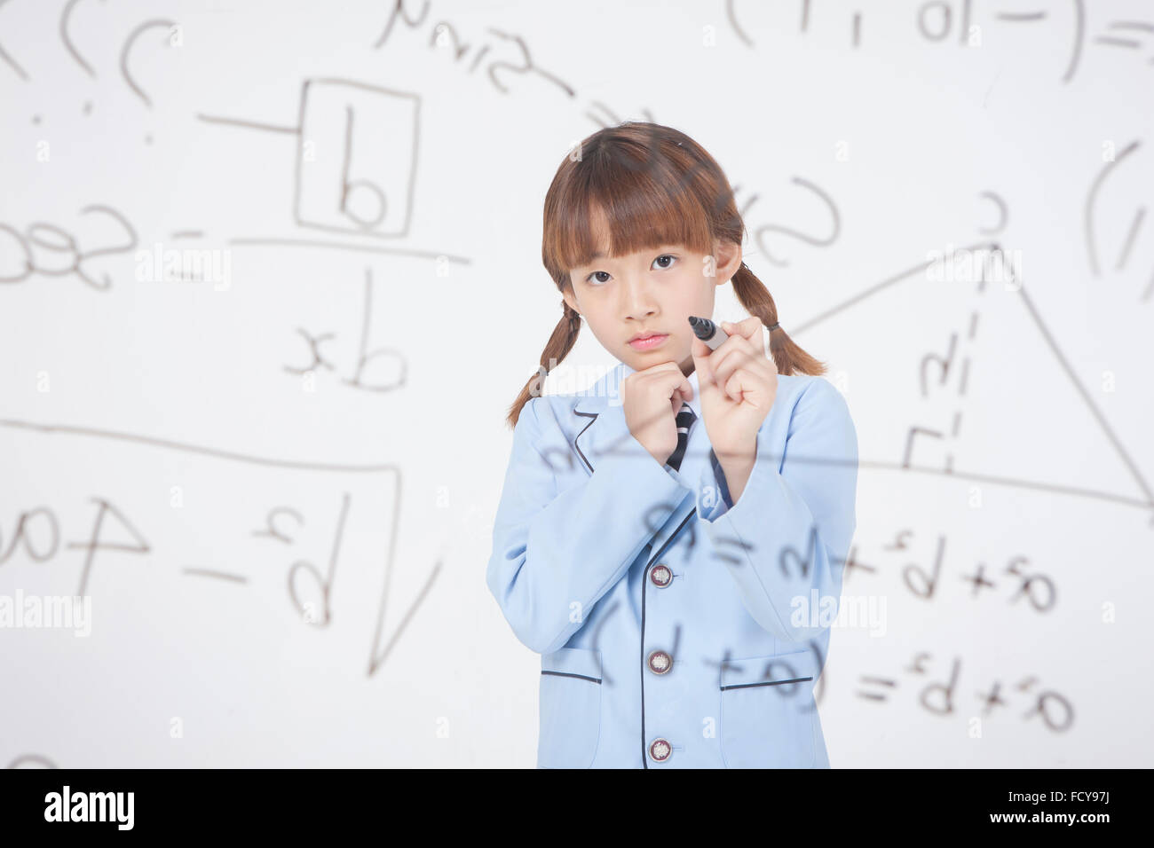 Elementary school girl in uniforms standing behind a transparent board ...