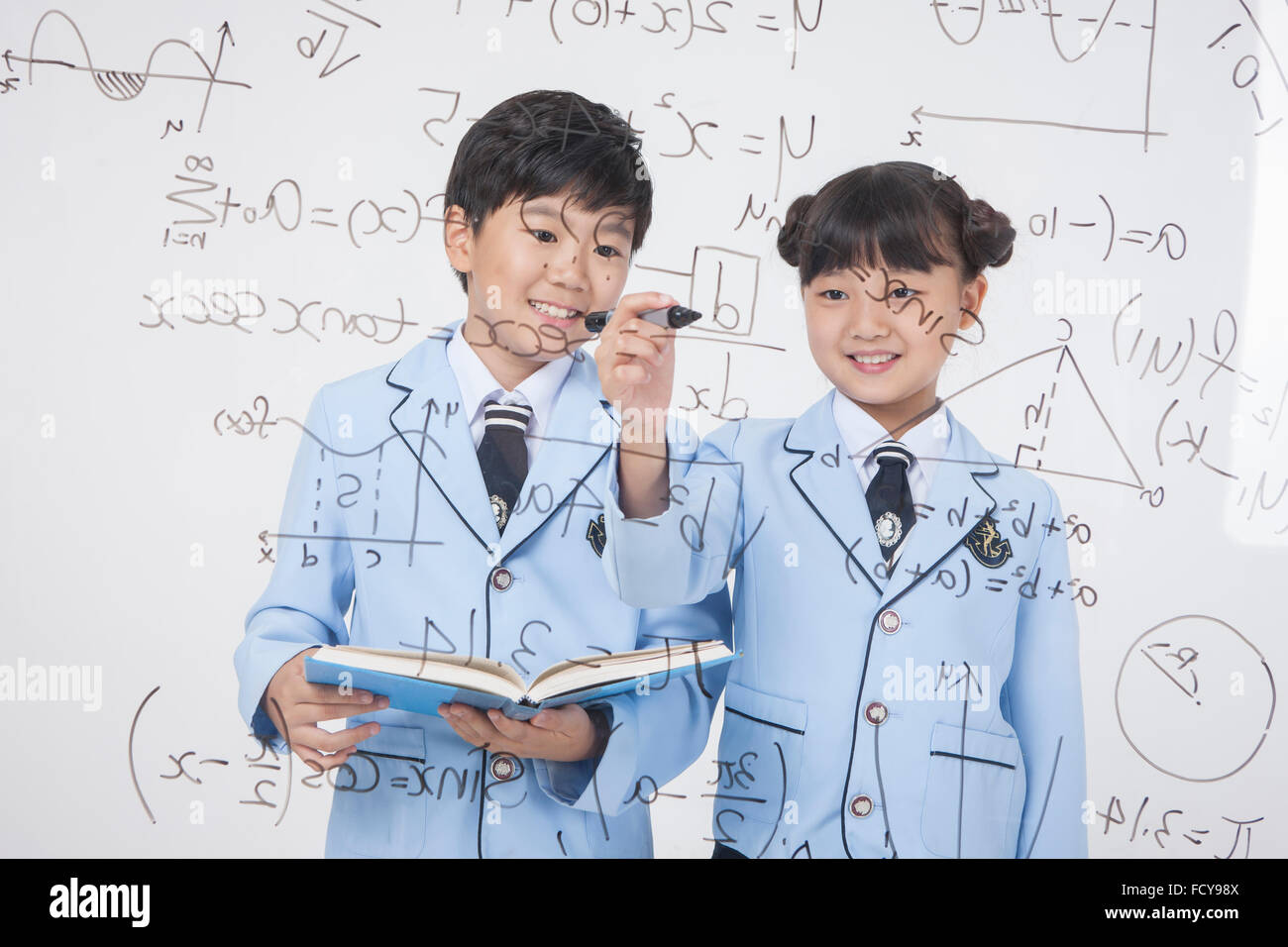 Elementary school boy and girl in uniforms behind transparent board ...