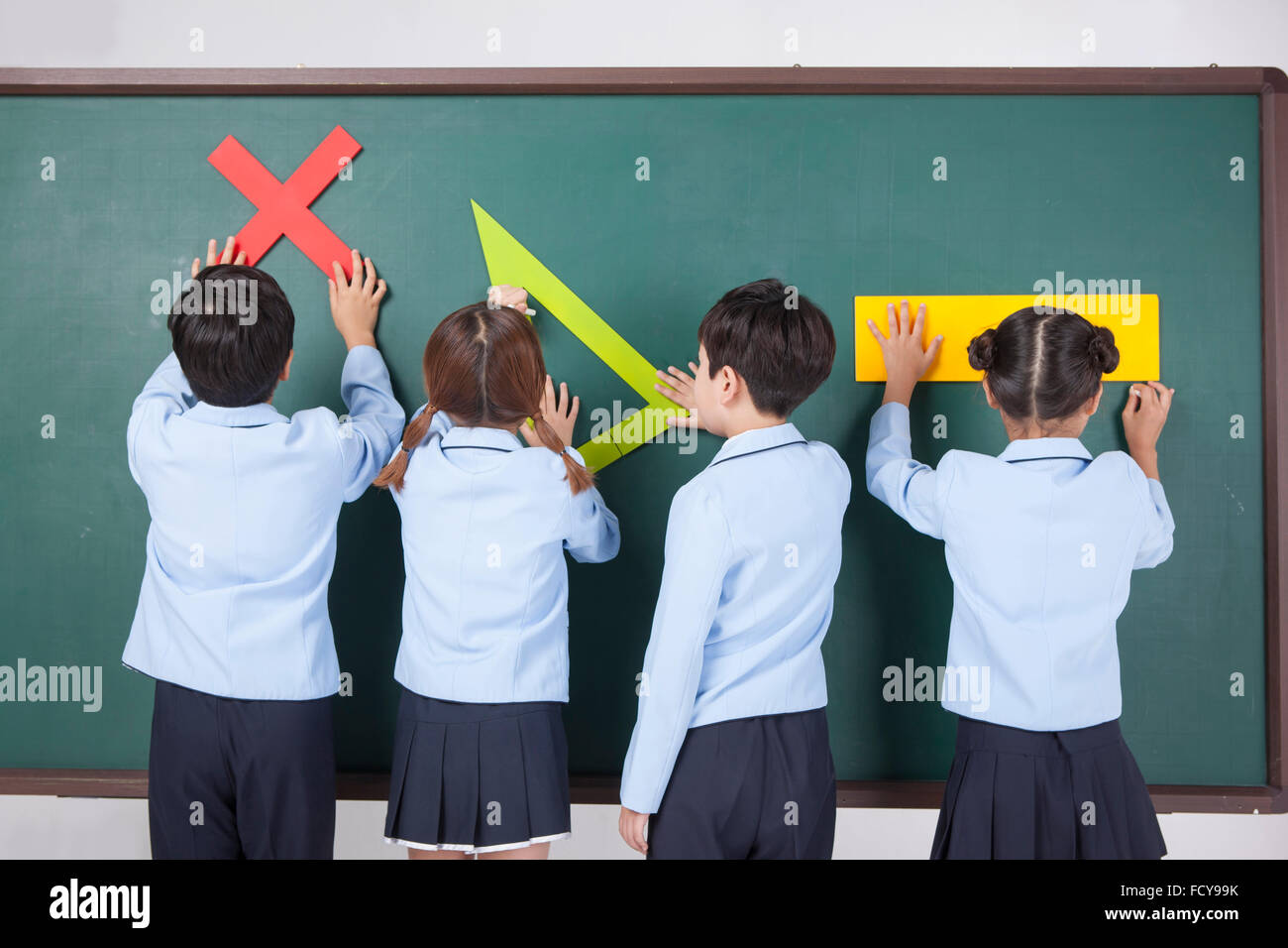 Four elementary school students holding an object related to math each ...