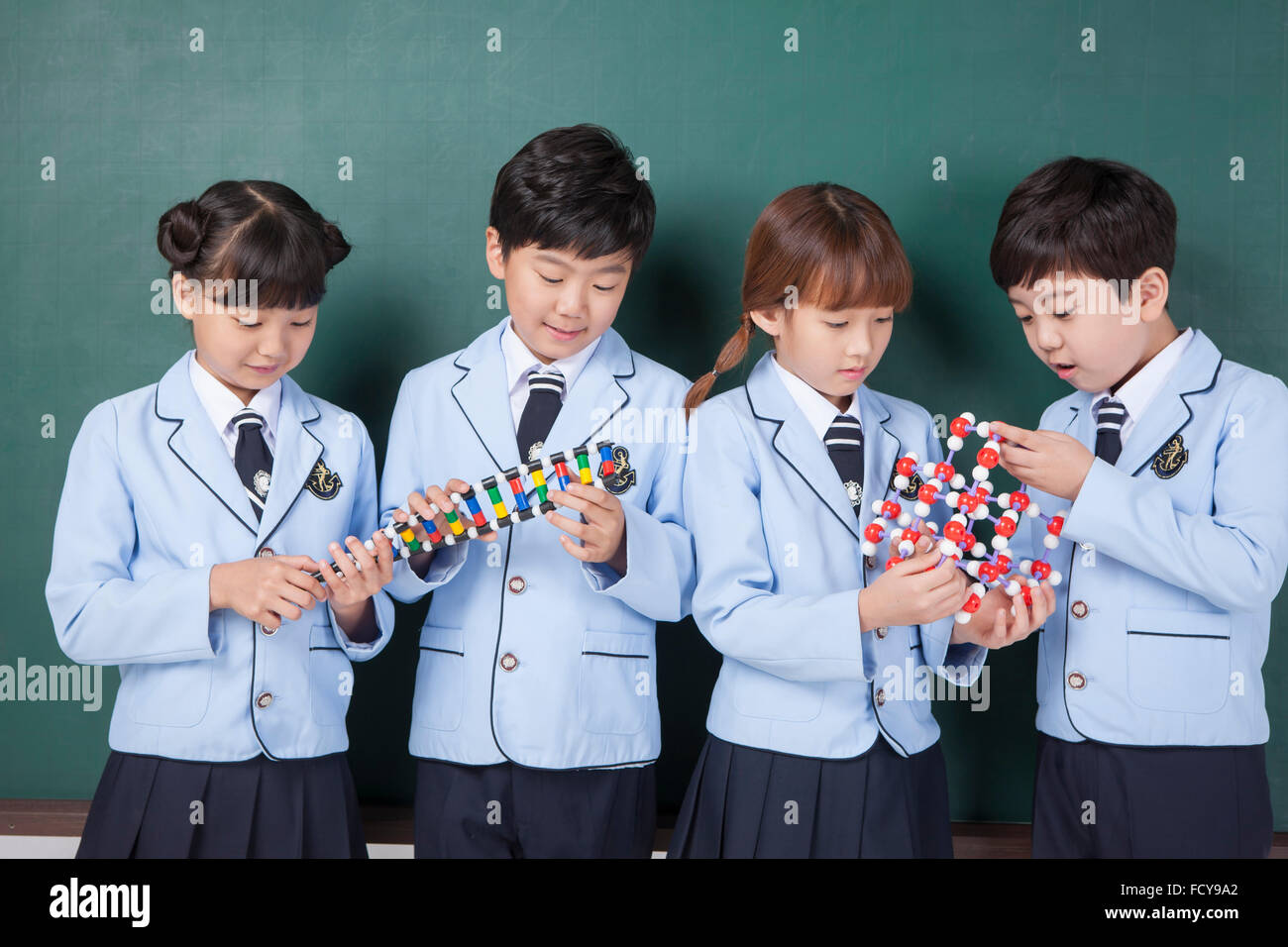 Four elementary school students holding molecular structures together ...