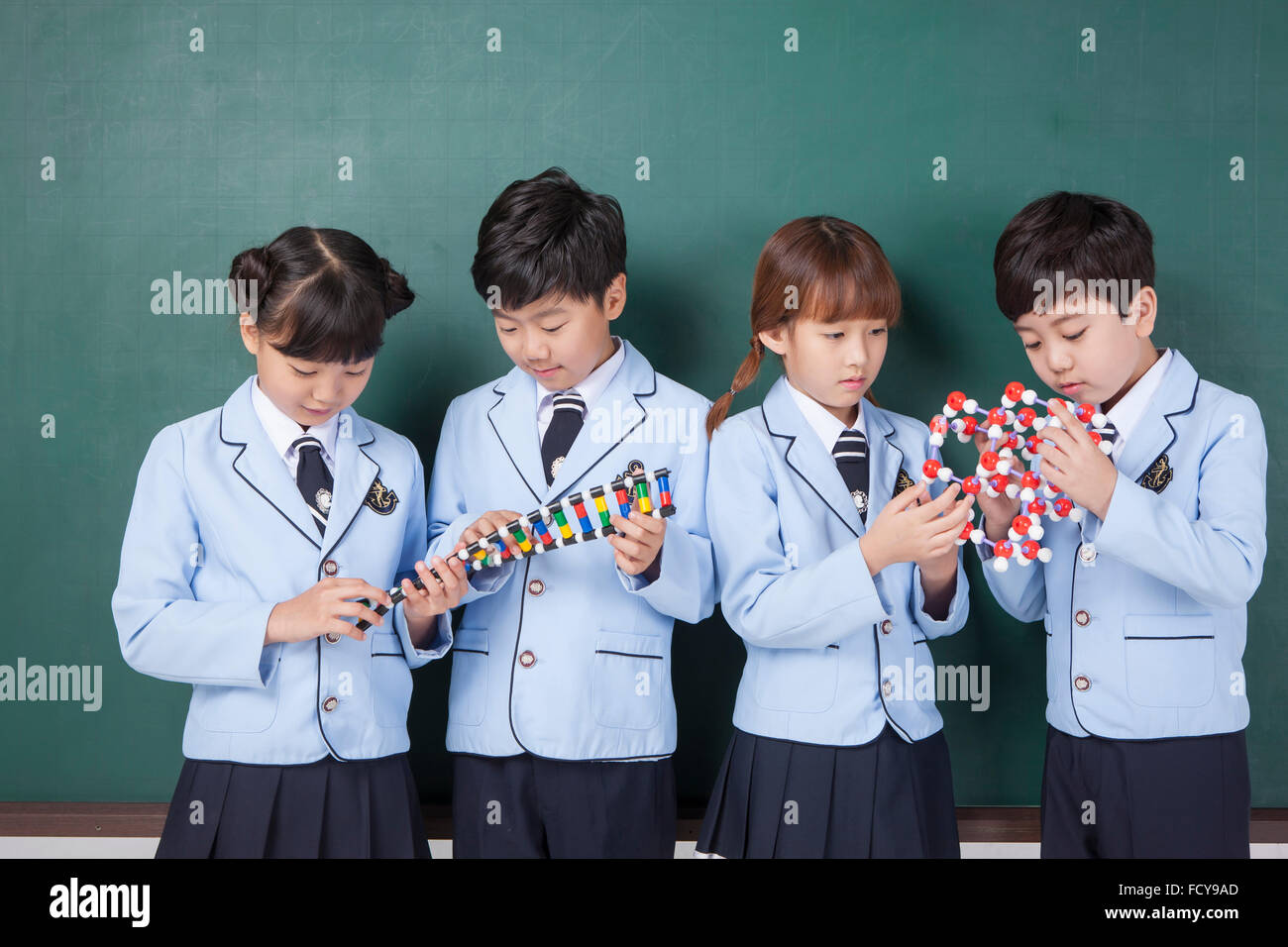 Four elementary school students holding molecular structures together ...