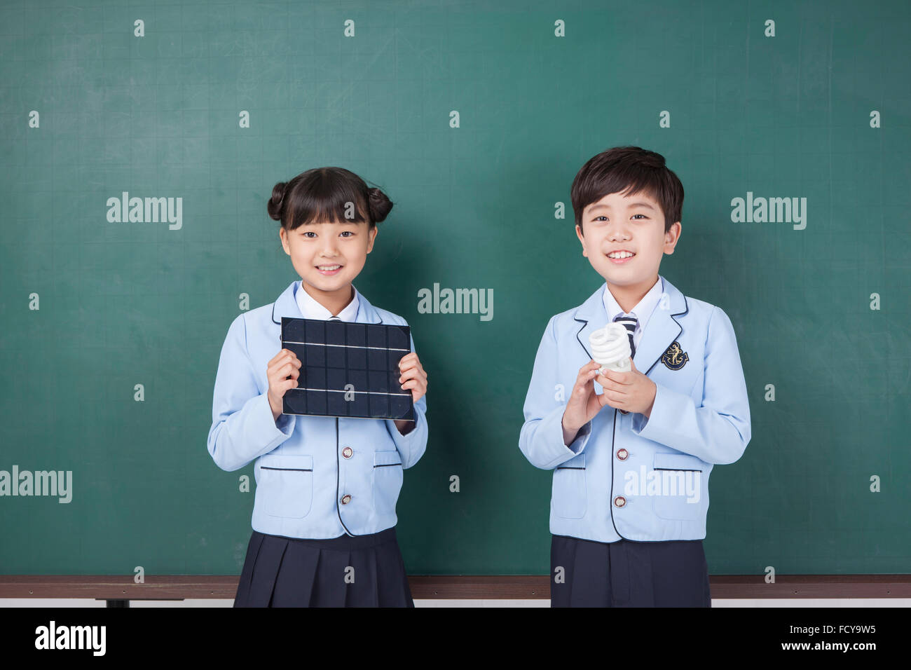 Two elementary school students in school uniforms holding a scientific ...