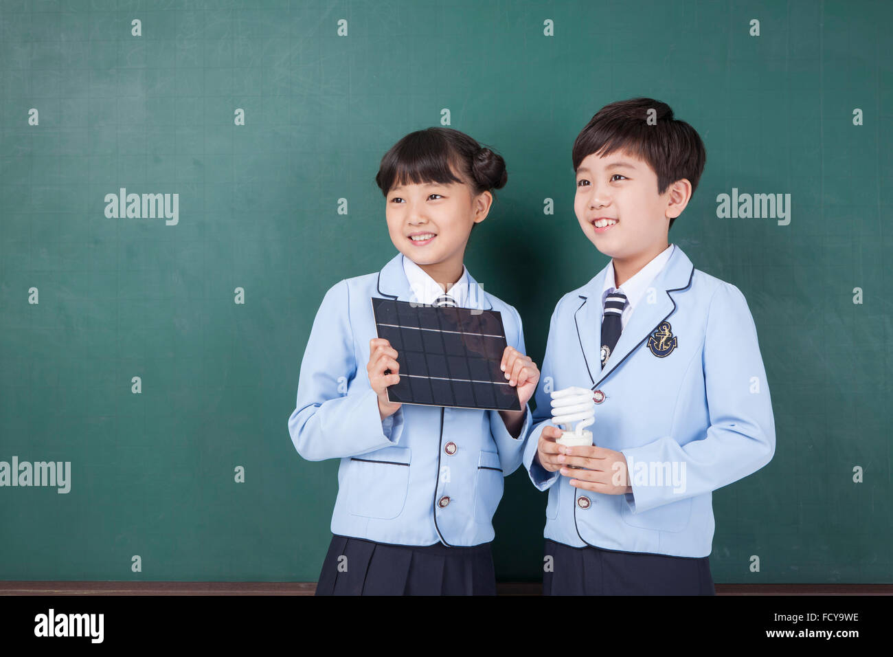 Two elementary school students in school uniforms holding a scientific ...