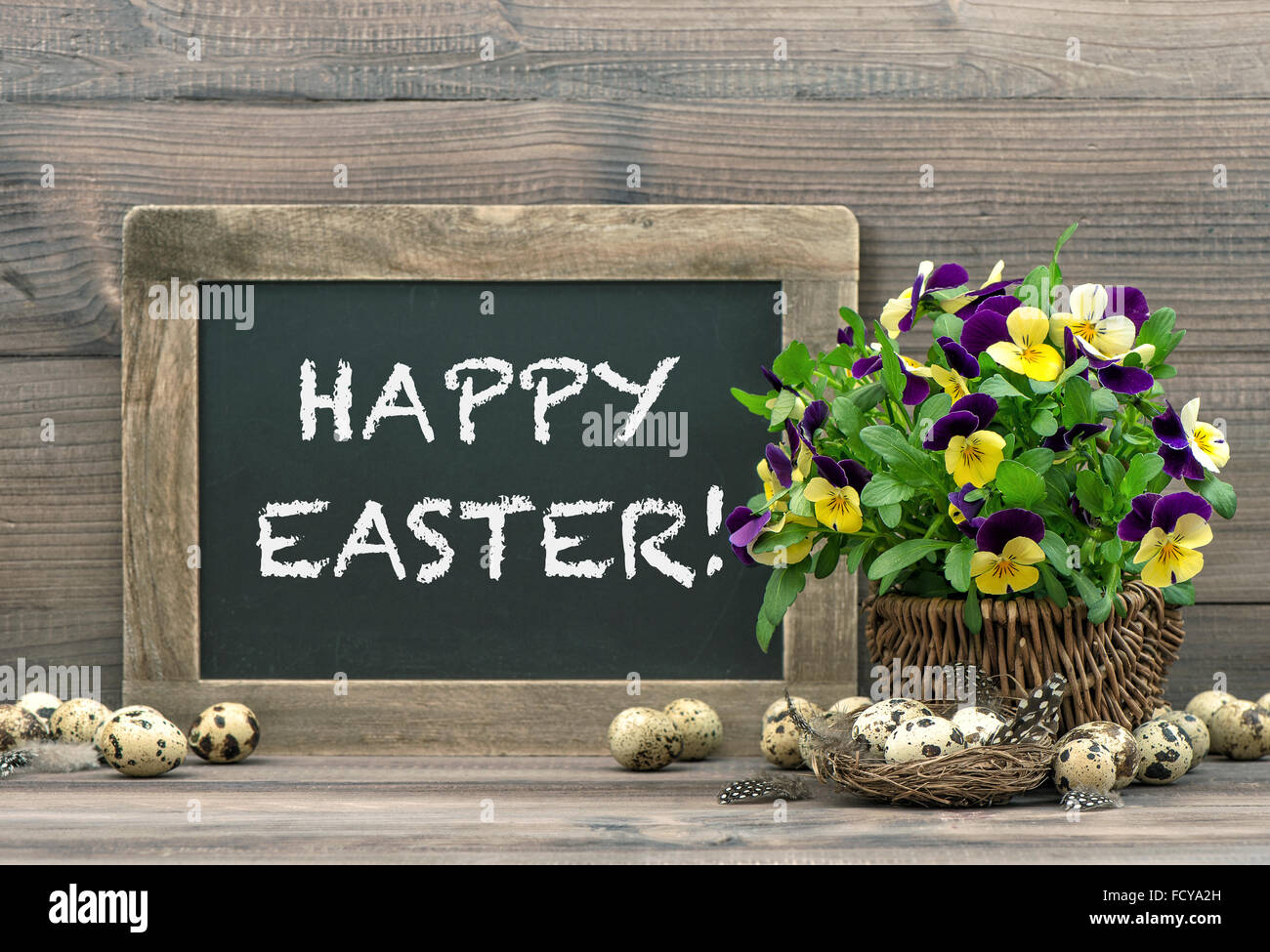 Easter decoration with eggs and pansy flowers. Vintage blackboard with ...