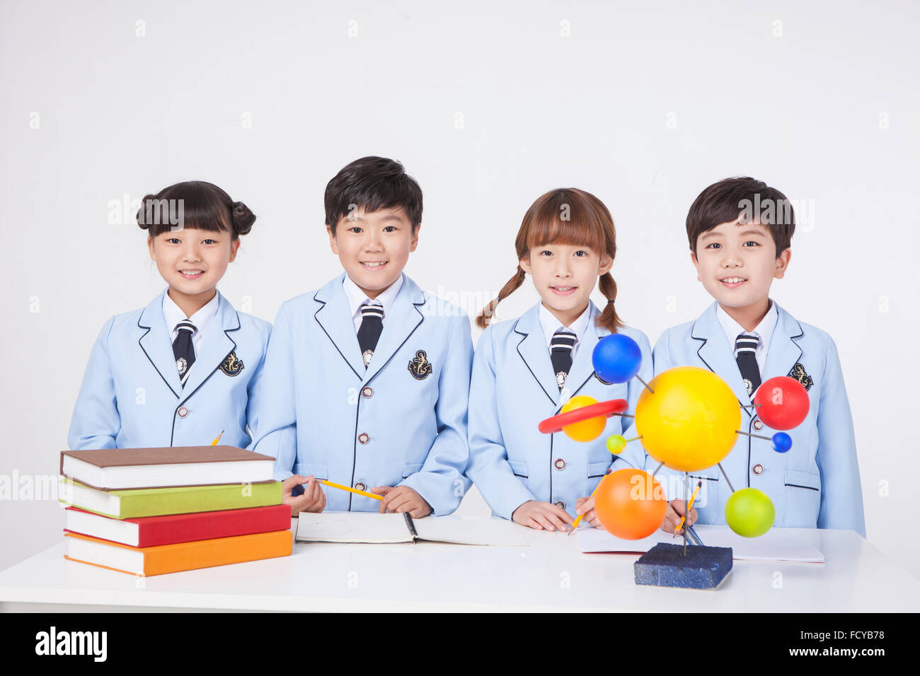 Four elementary school students in school uniform behind the desk with ...