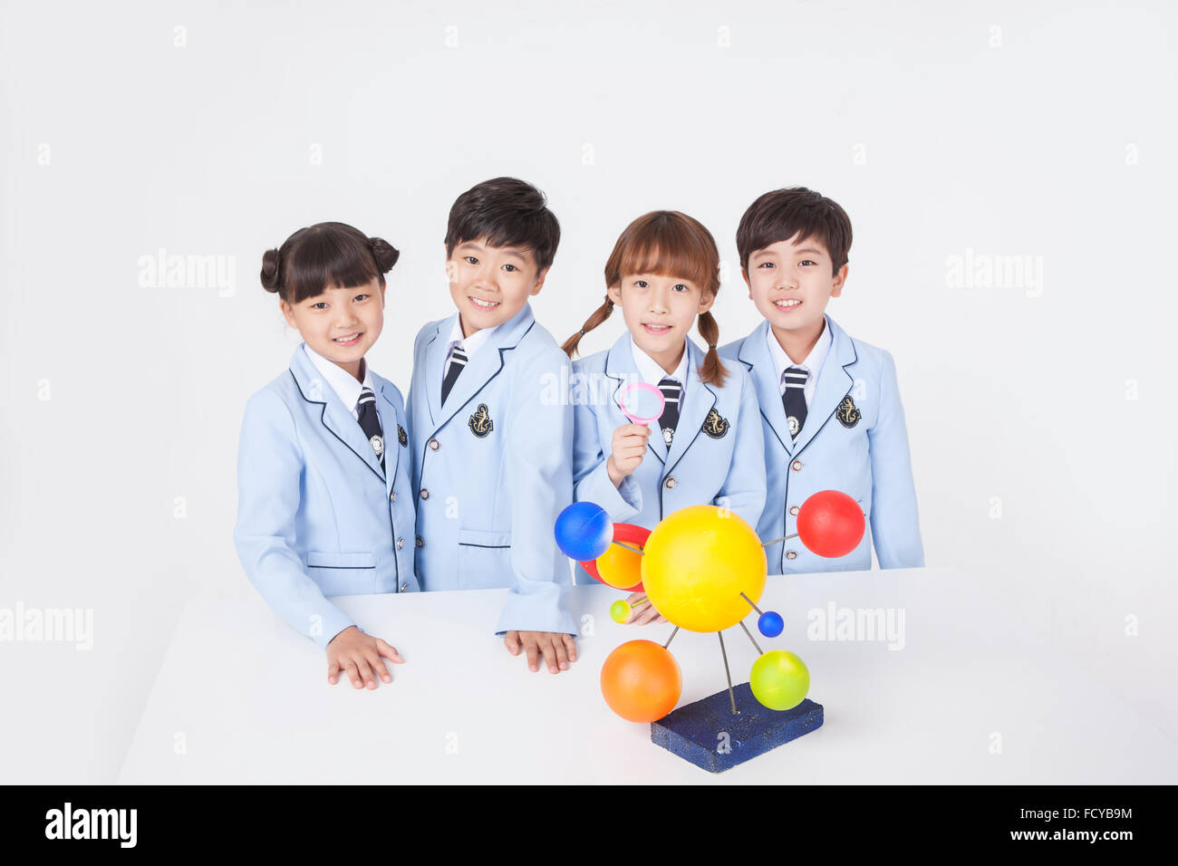 Four elementary school students behind the desk with planet models and ...