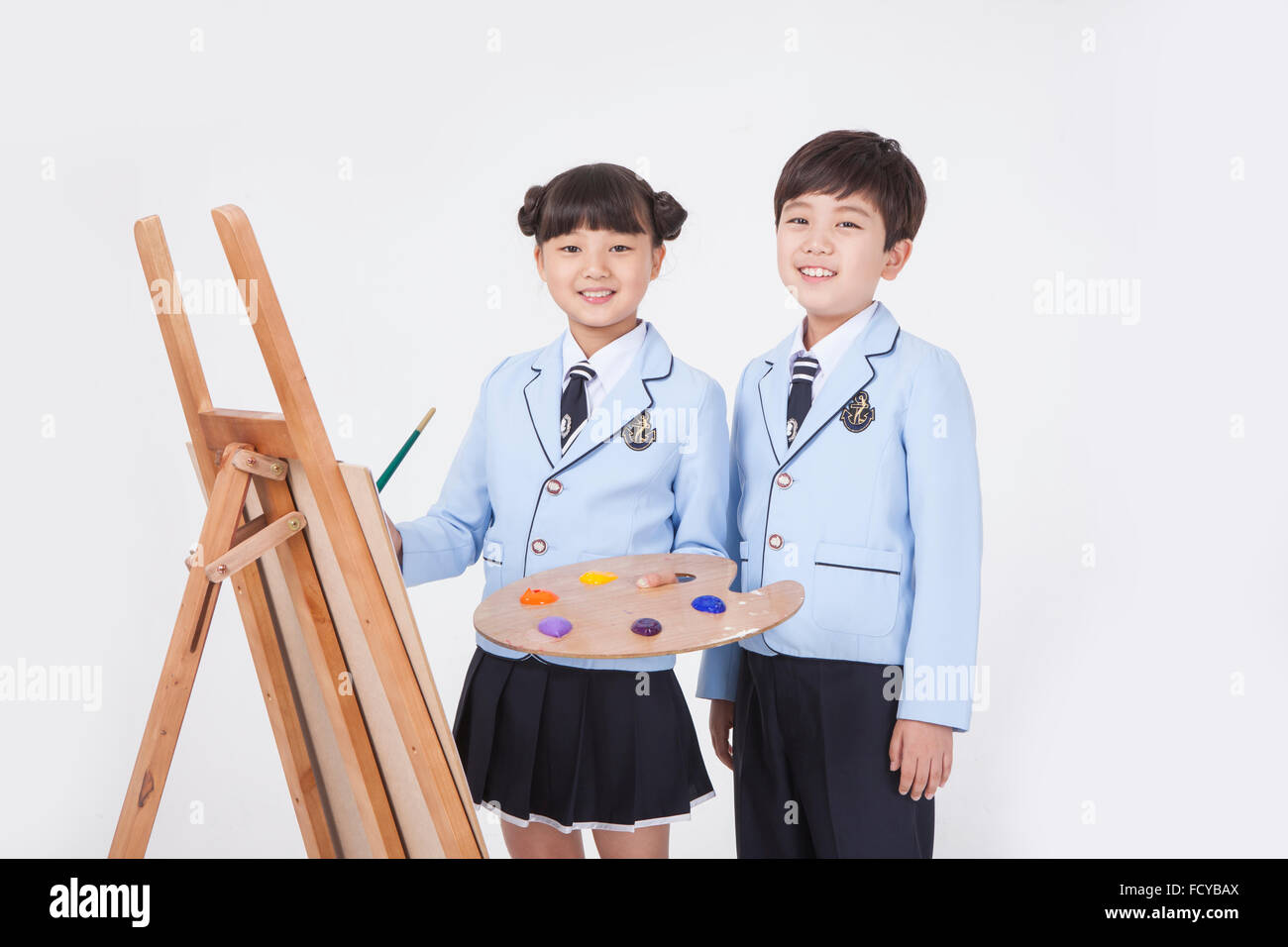 Two elementary school students in school uniforms standing with an ...