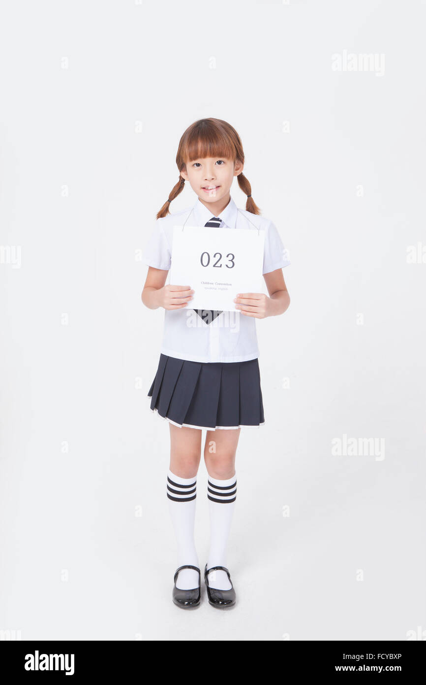 Elementary school girl in uniform holding a numbering tag and standing ...