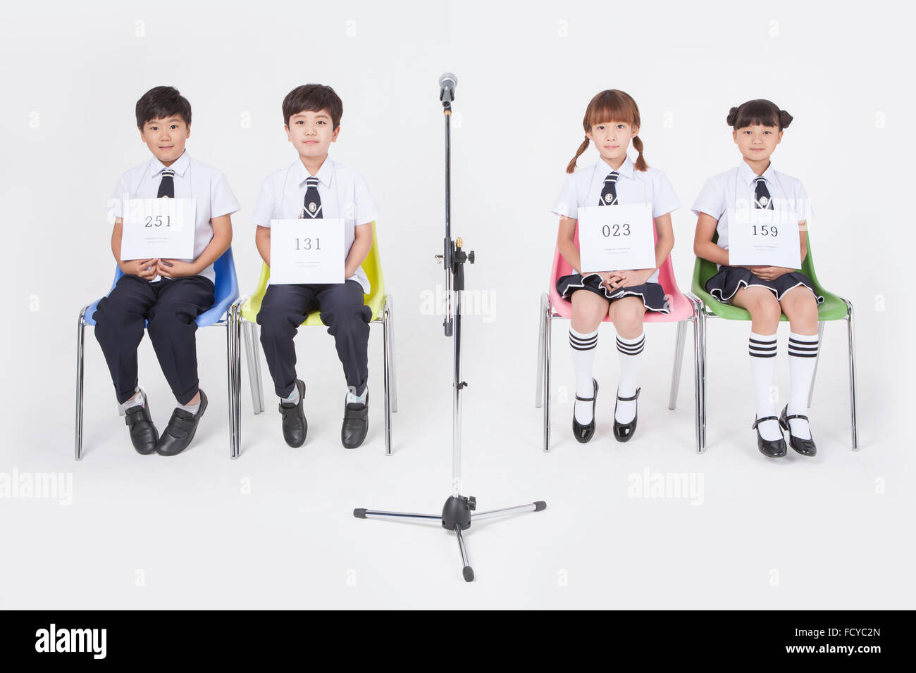 Four elementary school students in school uniforms seated on a chair ...