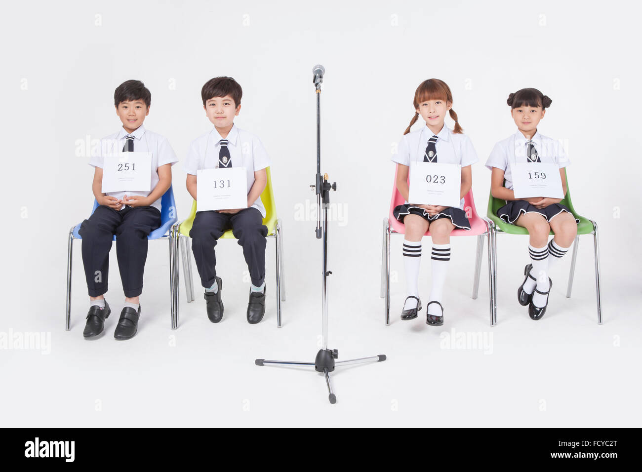 Four elementary school students in school uniforms seated on a chair ...