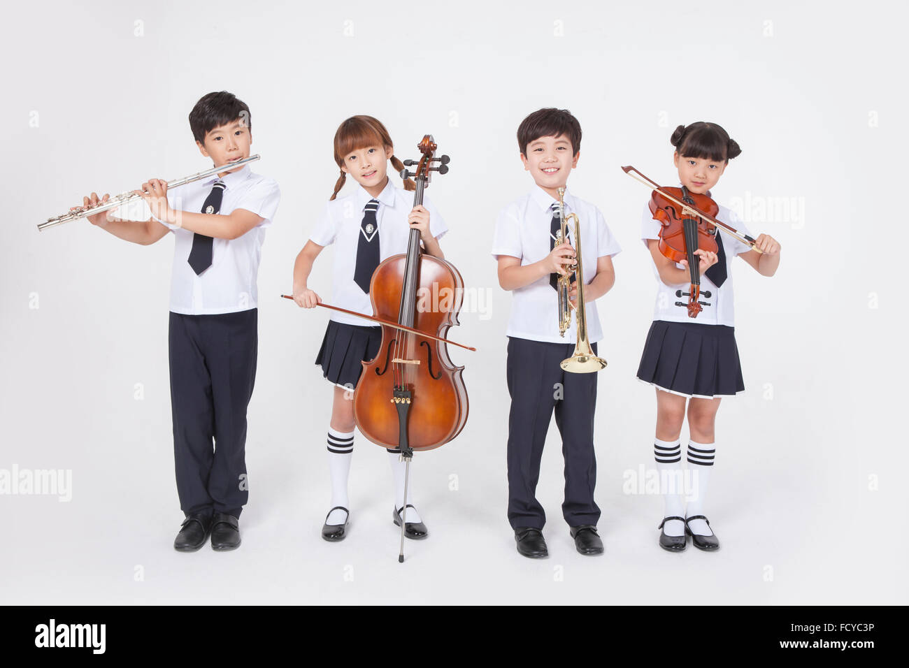 Four elementary school students in school uniforms standing and playing ...