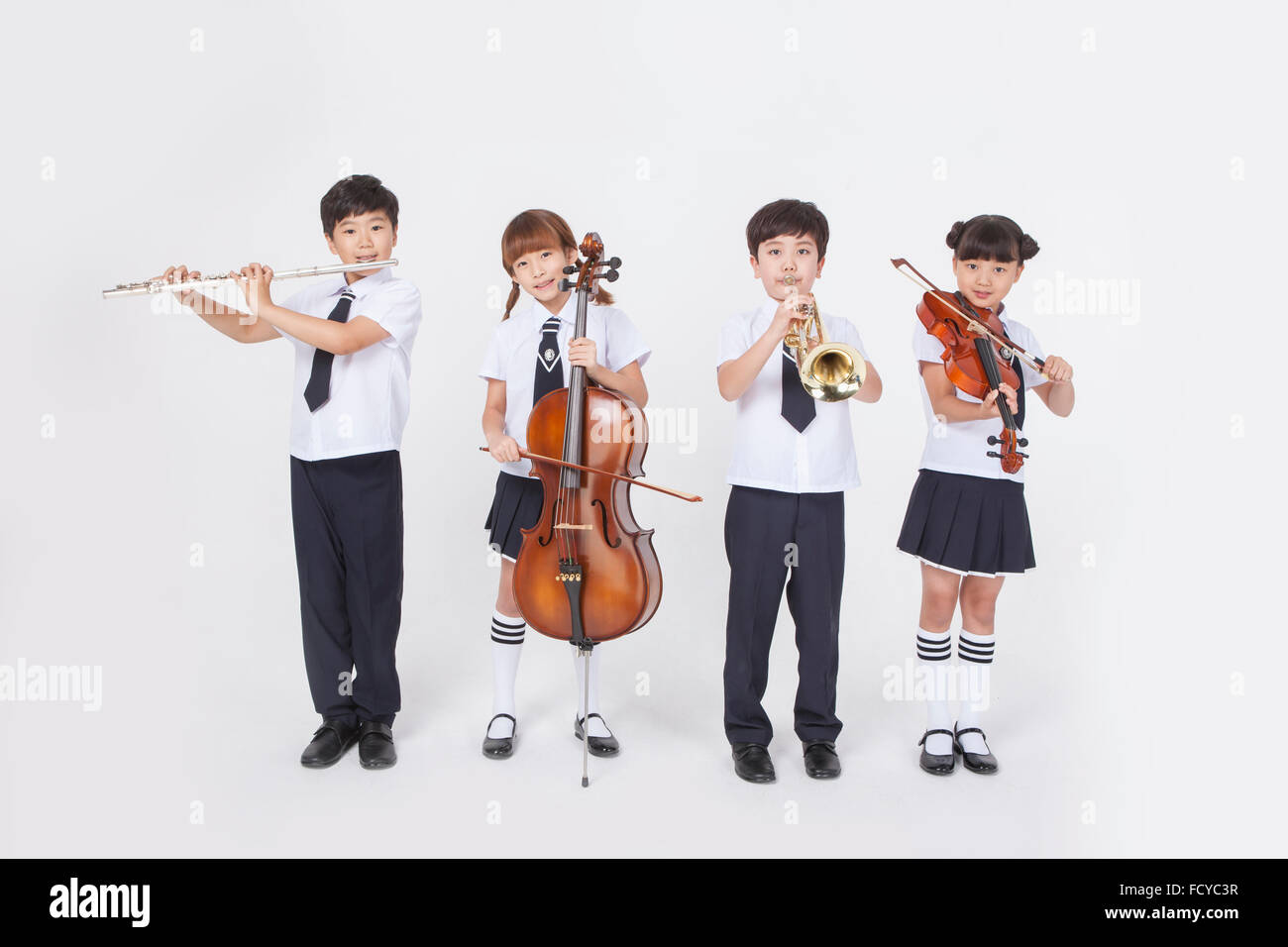 Four elementary school students in school uniforms standing and playing ...