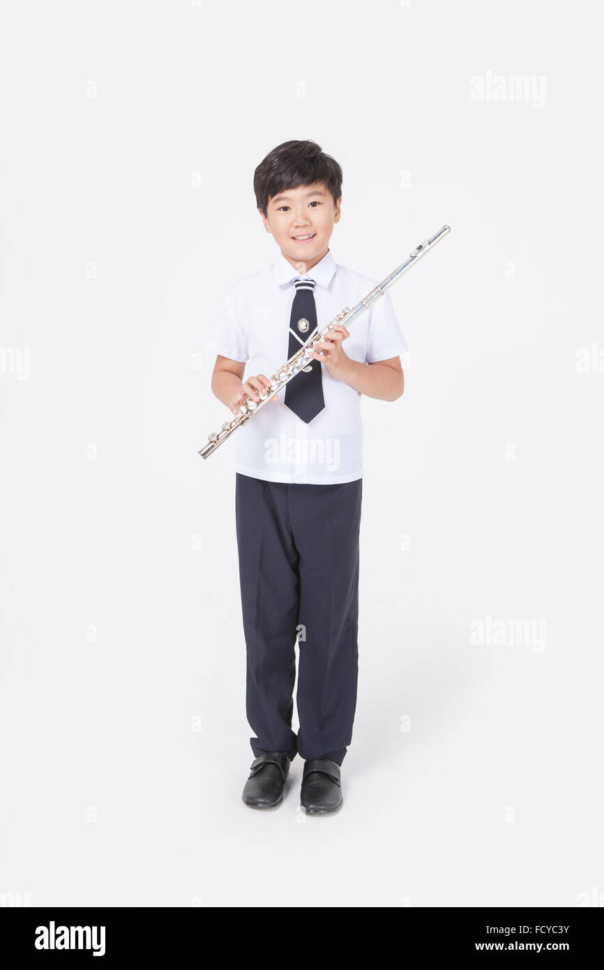 Elementary school boy in school uniforms standing and holding a flute ...