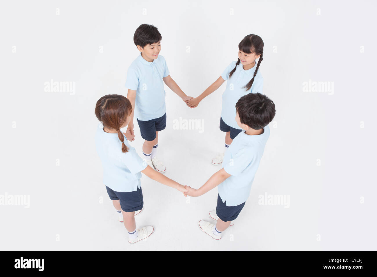 High angle of four elementary school students holding each other's hand ...