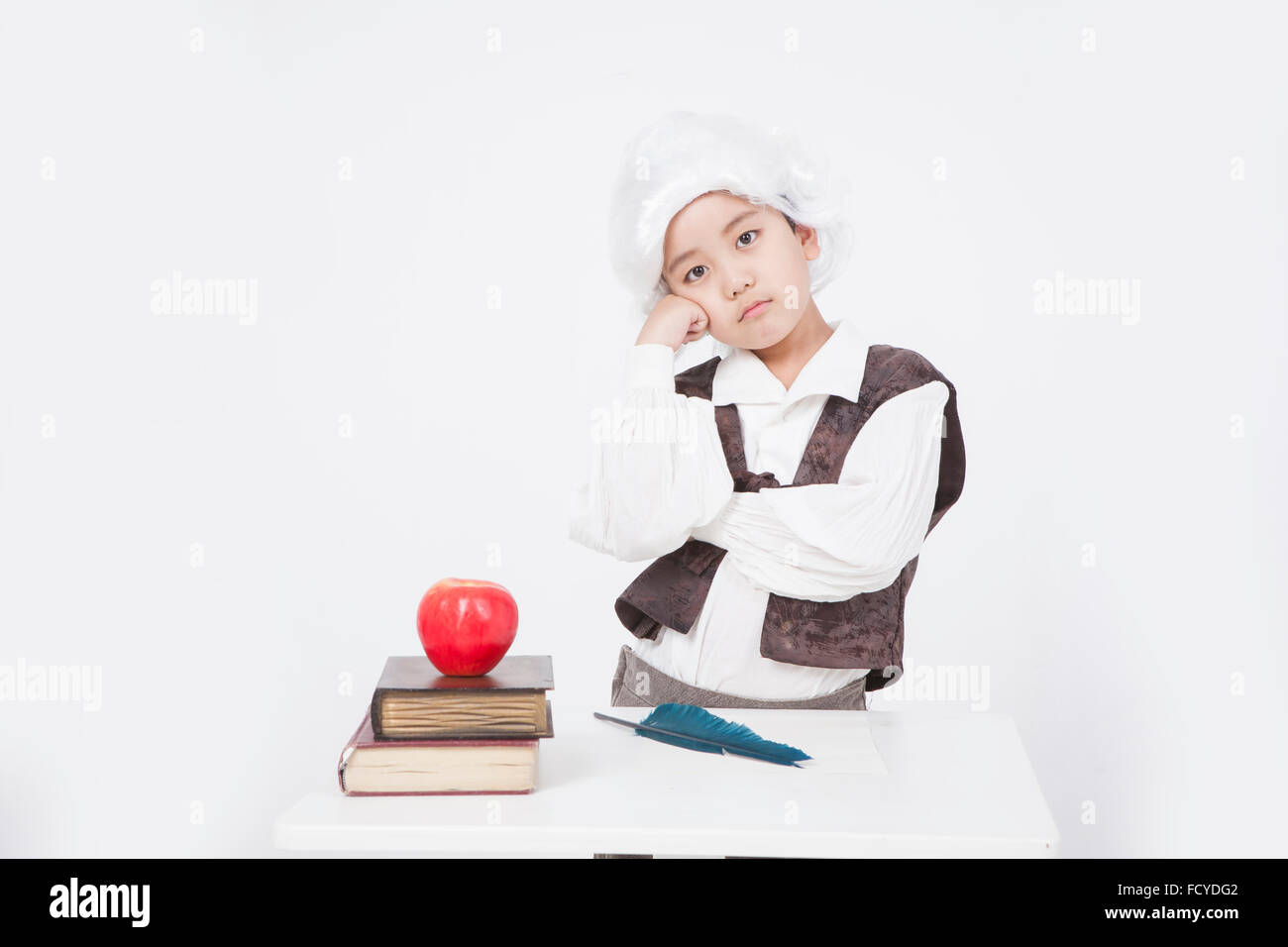 Boy in classical scholar style thinking at desk with an apple on old ...