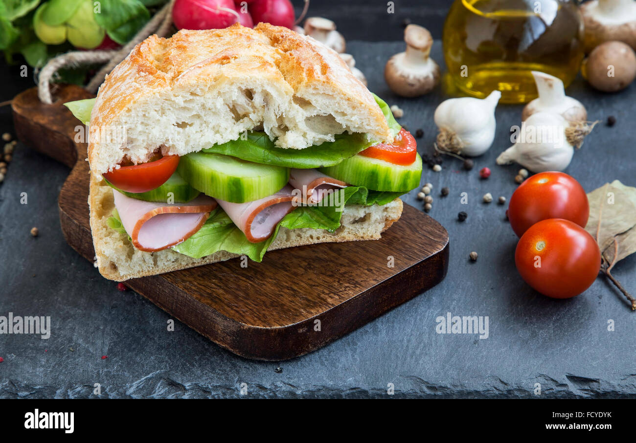Rustic sandwich with ham, ciabatta bread,fresh salad,tomatoes and ...