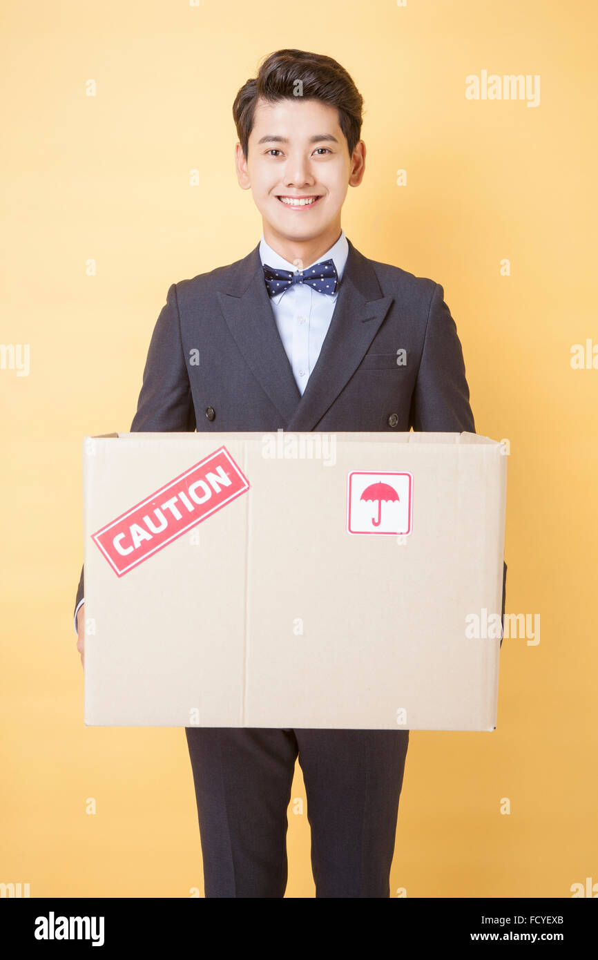 Man in suit and bow tie holding a box with caution sign with the ...