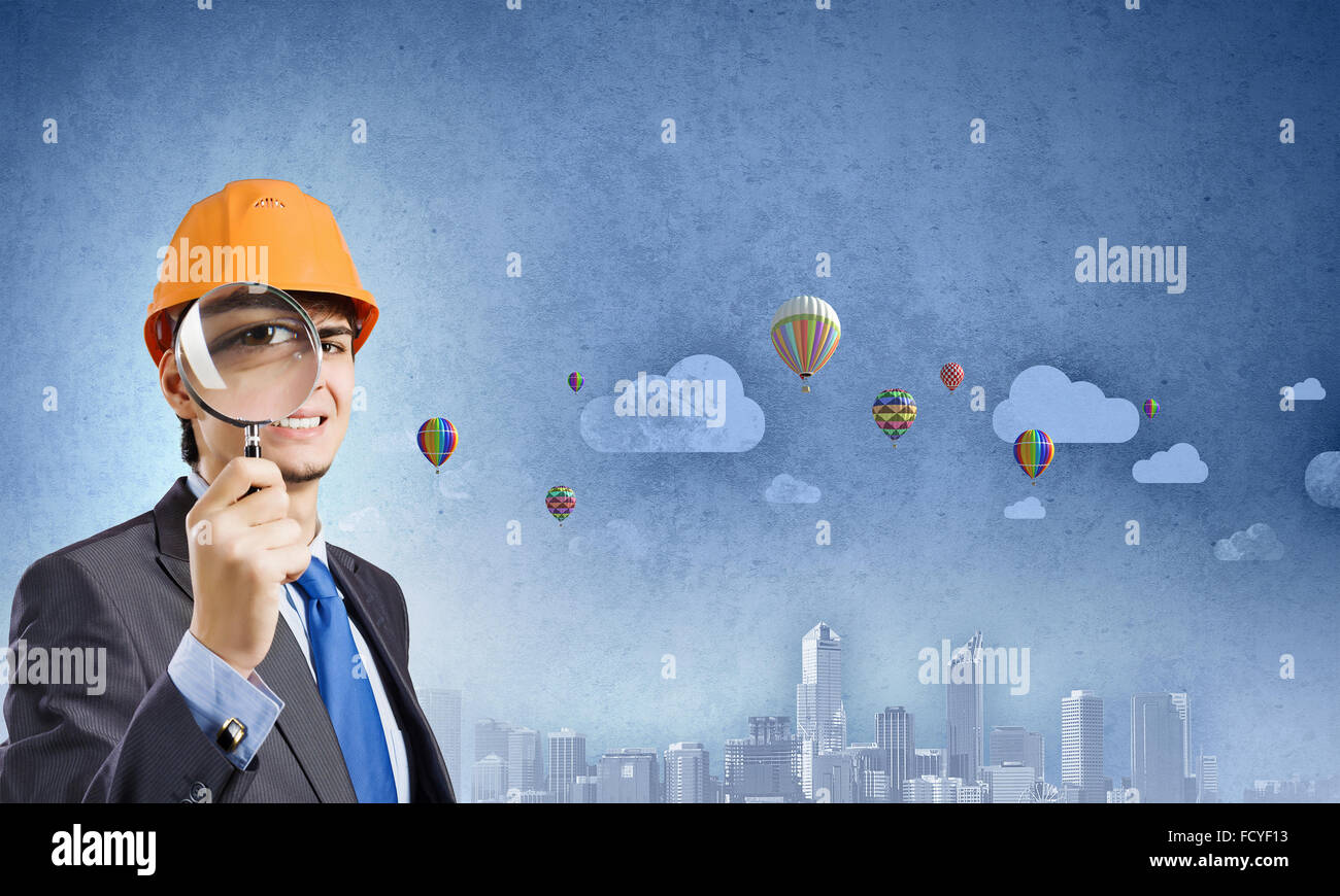 Young man engineer with magnifier against city background Stock Photo ...