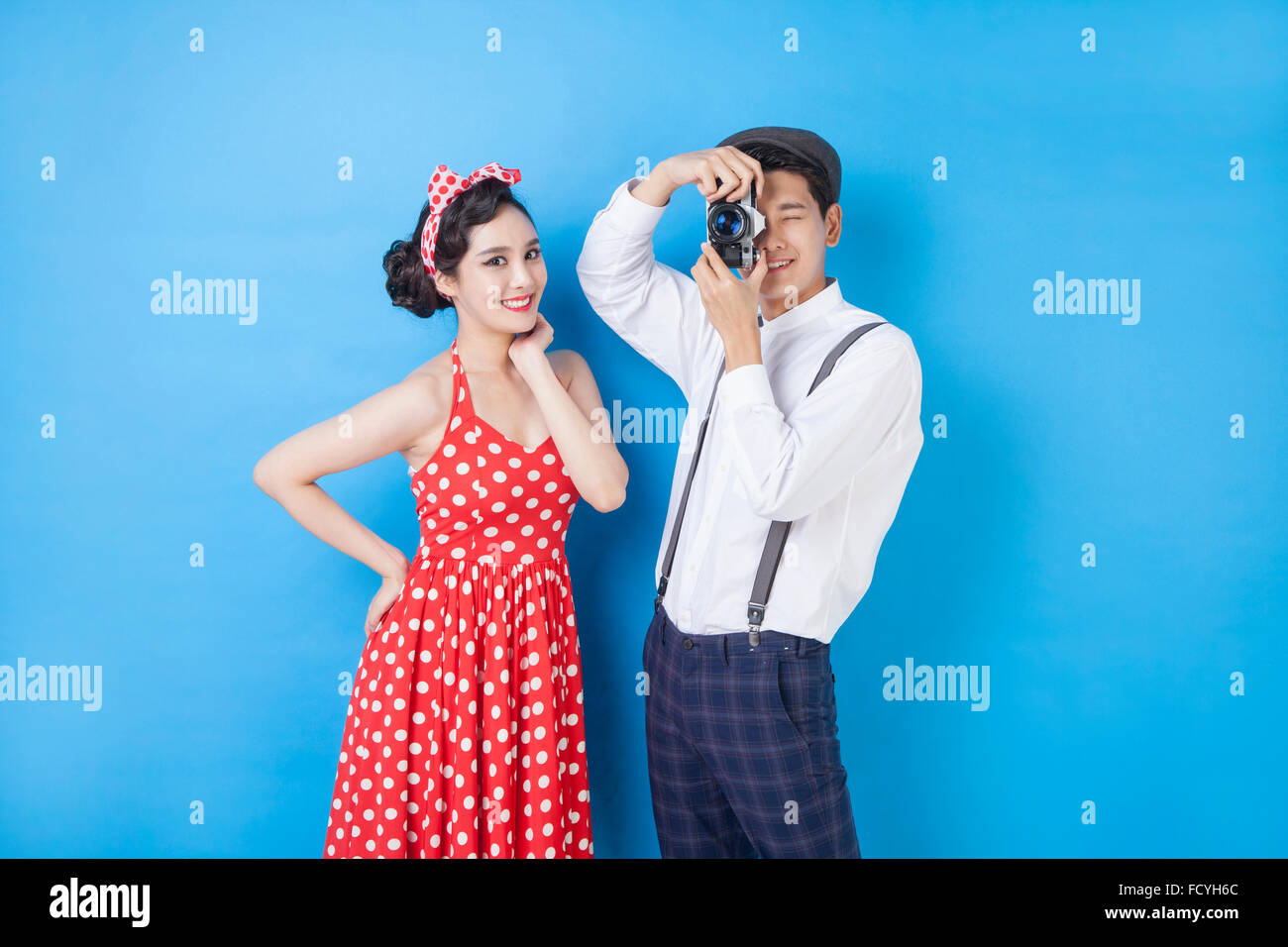 Couple in retro style fashion staring forward with a smile and the man ...