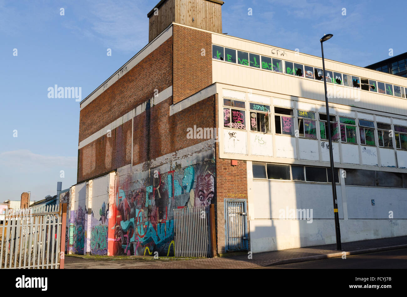 Boarded up 1960s factory with offices above and graffiti painted on ...