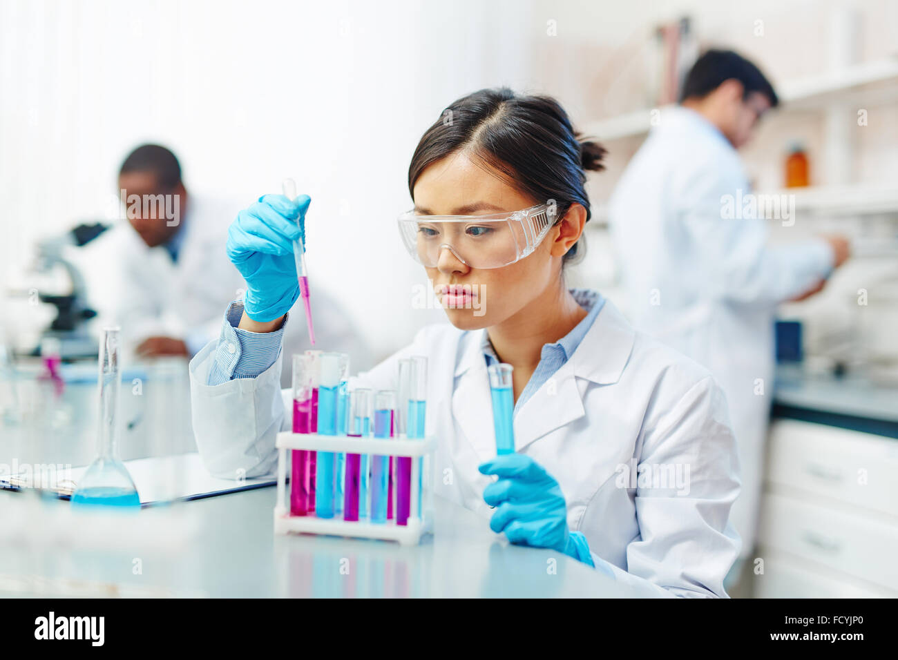 Young scientist making experiment with liquid substances in flasks ...