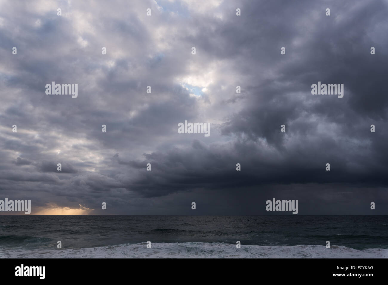 Approaching storm cloud with rain over the sea during sunrise Stock ...