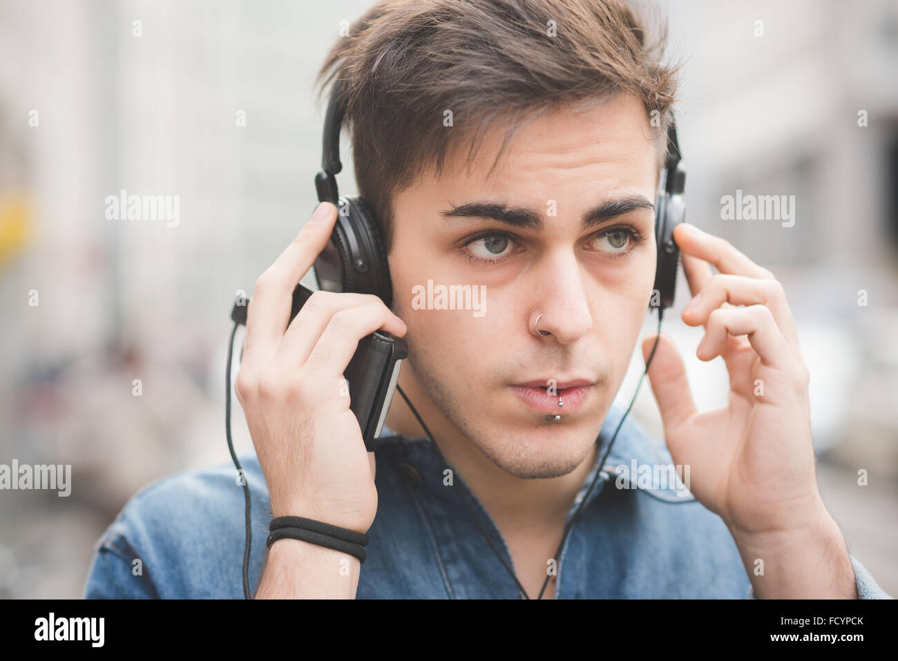 Portrait of young handsome alternative dark model man listening to ...