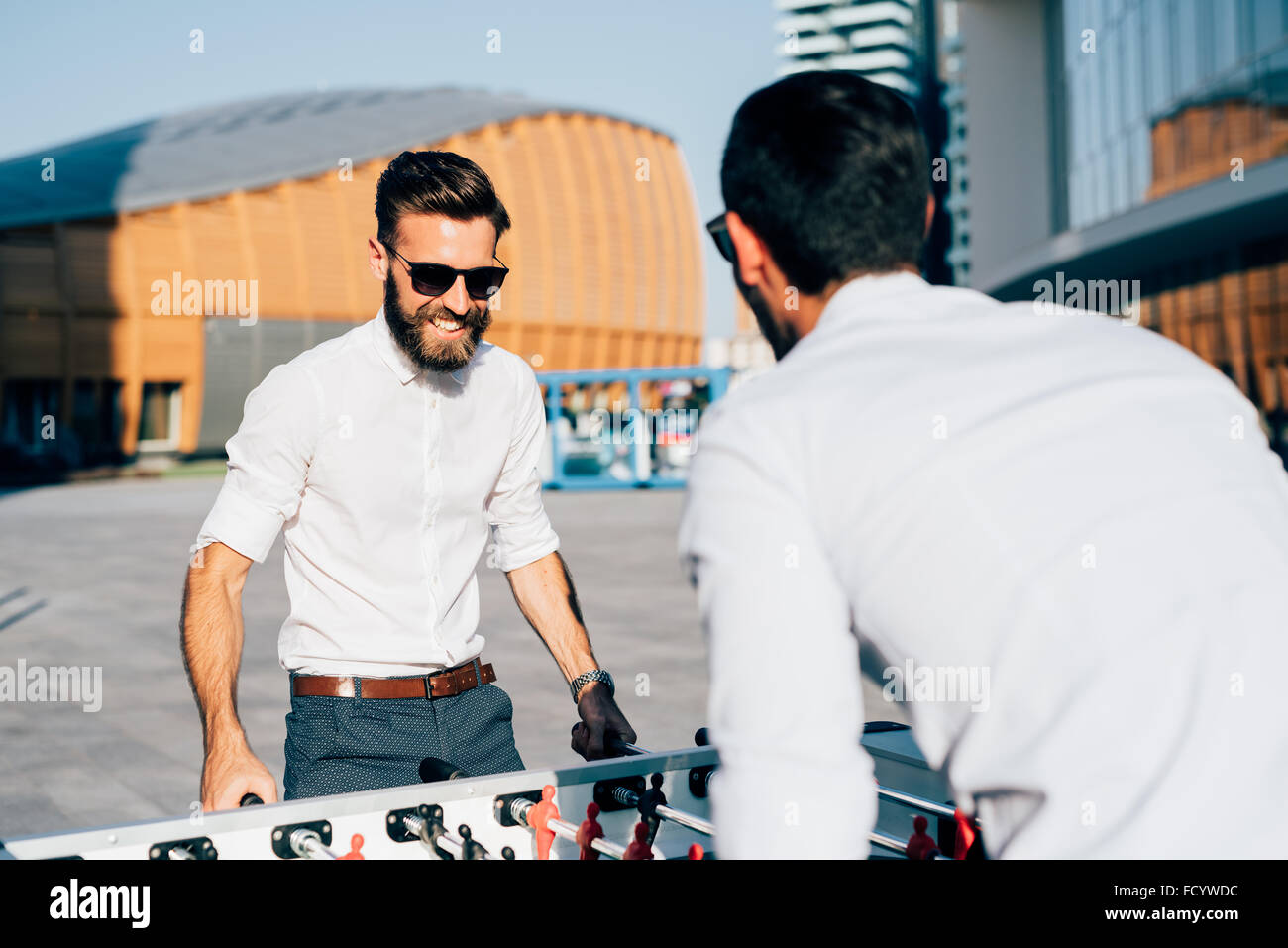 Knee figure of two modern bearded businessman playing table football ...
