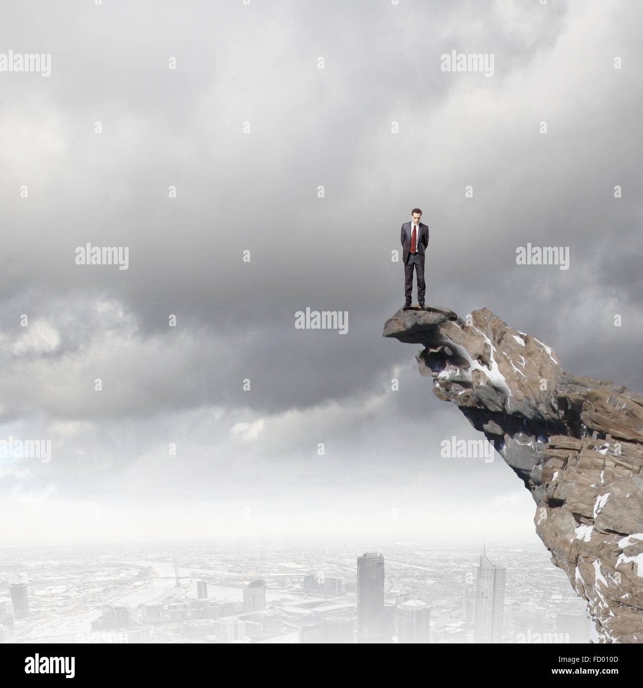 Young businessman standing on edge of rock mountain Stock Photo - Alamy