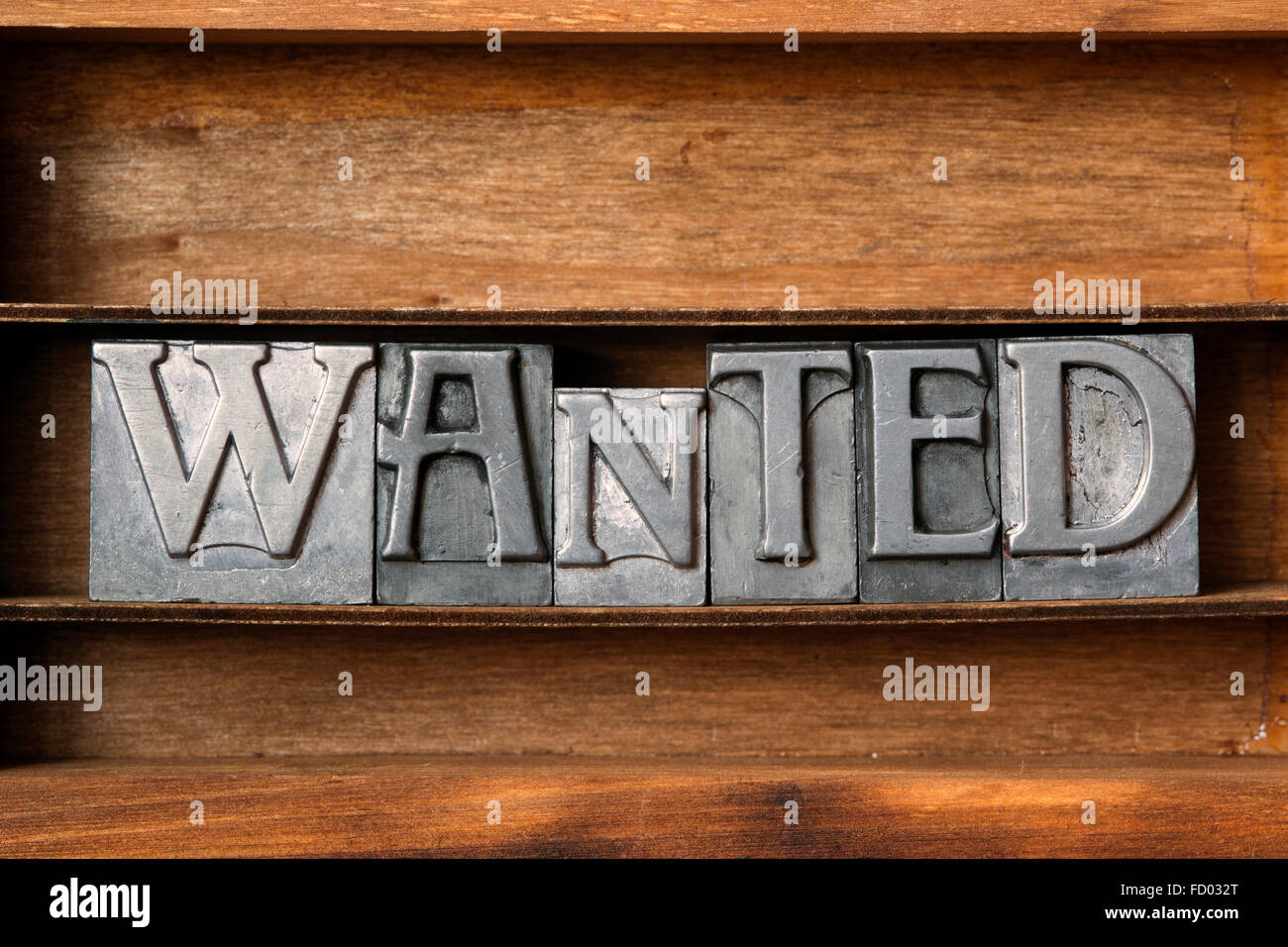 wanted word made from metallic letterpress type on wooden tray Stock ...