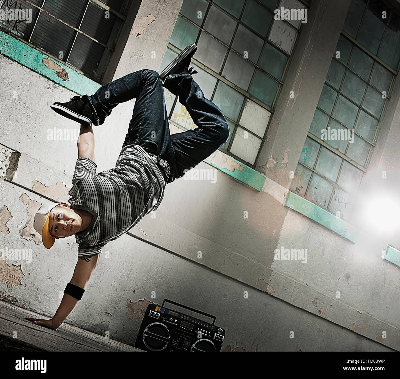 A young man breakdancing on the street of a city, doing a one handed ...