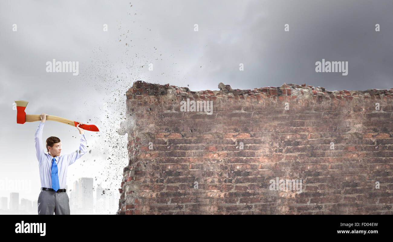 Young businessman breaking cement wall with axe Stock Photo - Alamy