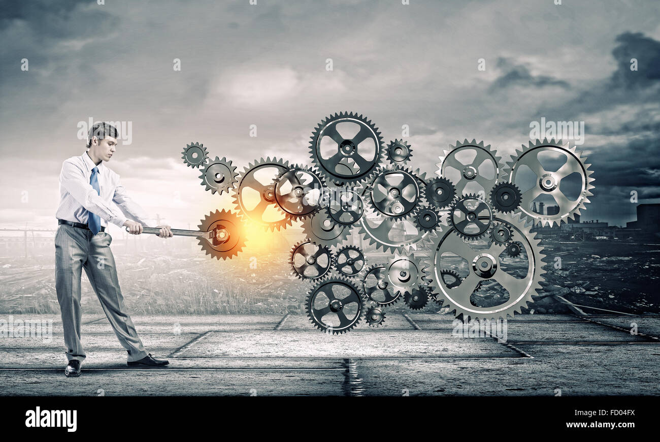 Young businessman fixing gears mechanism with wrench Stock Photo - Alamy