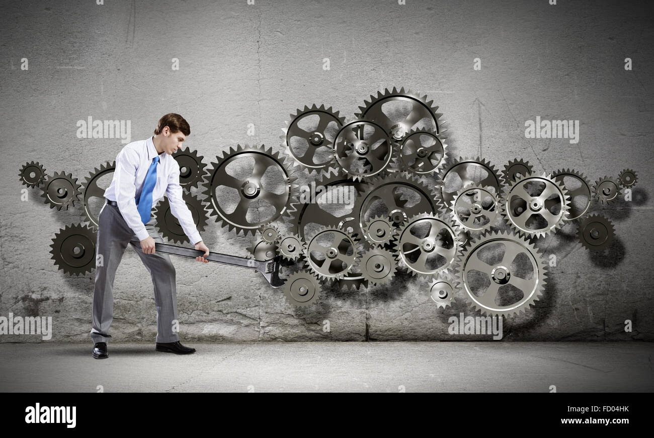 Young businessman fixing gears mechanism with wrench Stock Photo - Alamy
