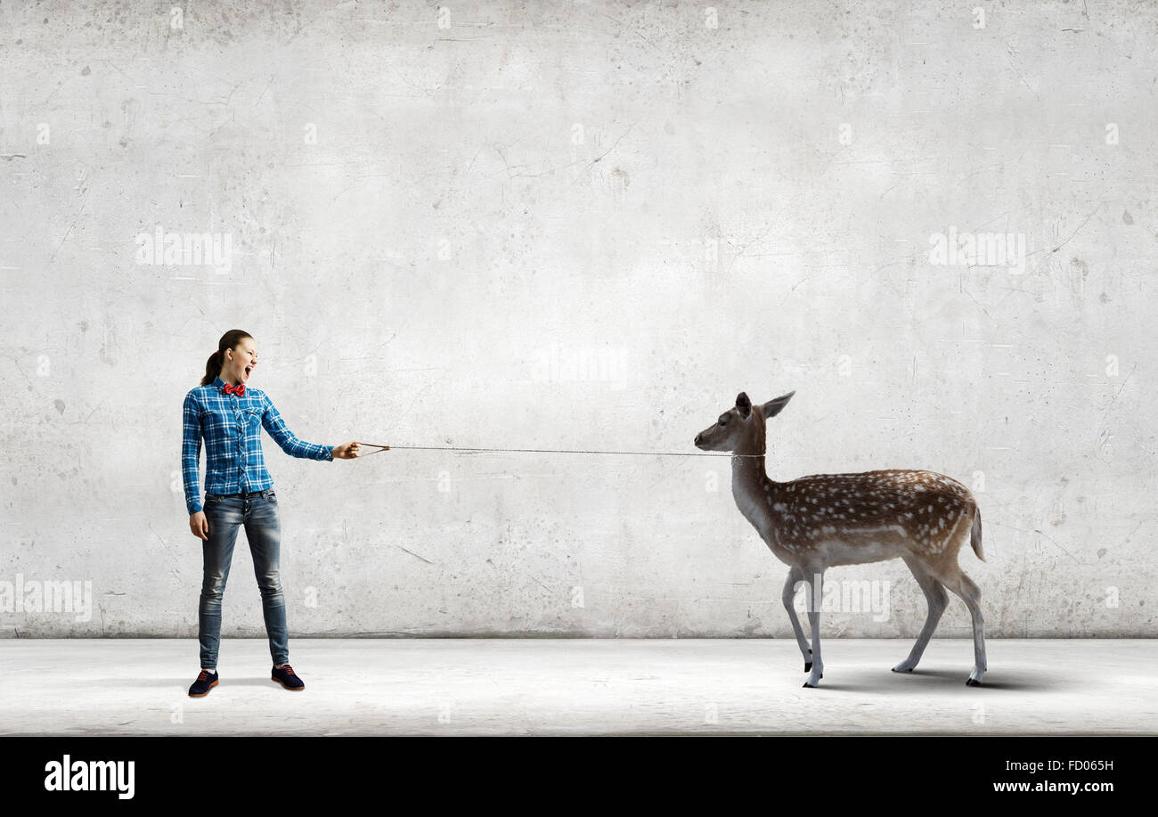 Young woman in casual holding fawn on lead Stock Photo - Alamy