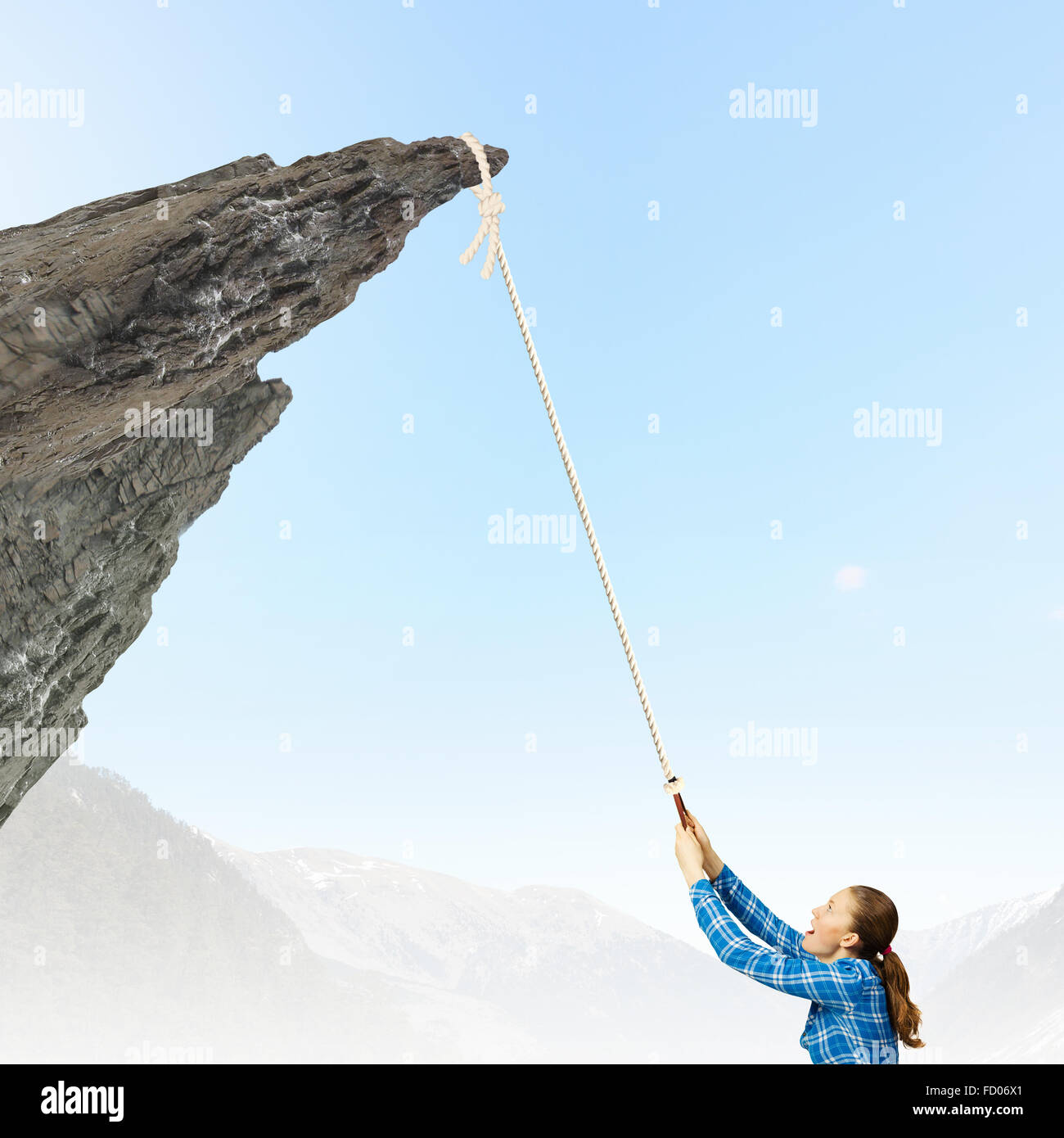 Young woman climbing rock with help of rope Stock Photo - Alamy