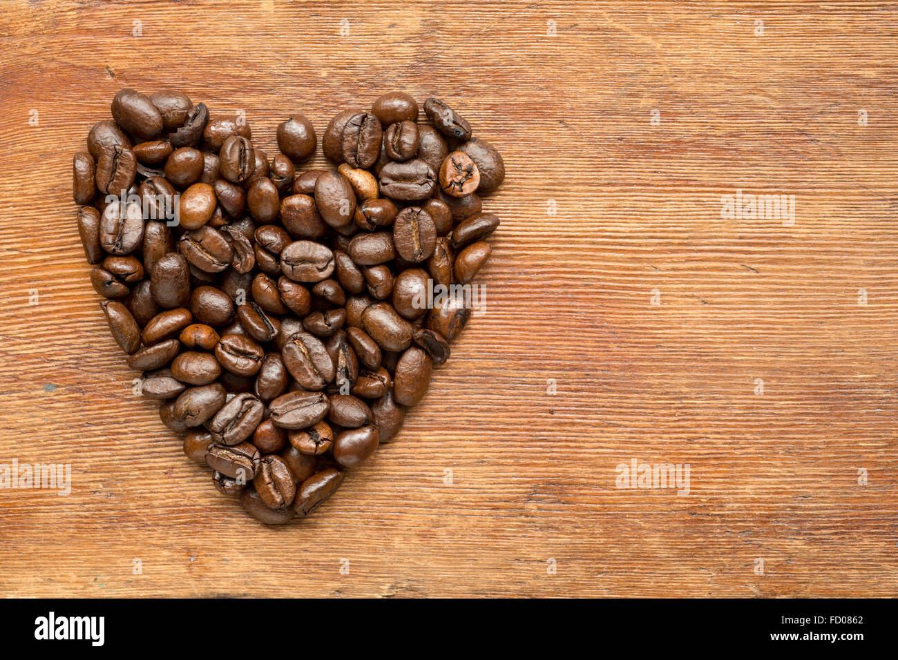 coffee heart symbol made from roasted grains on vintage wooden surface ...