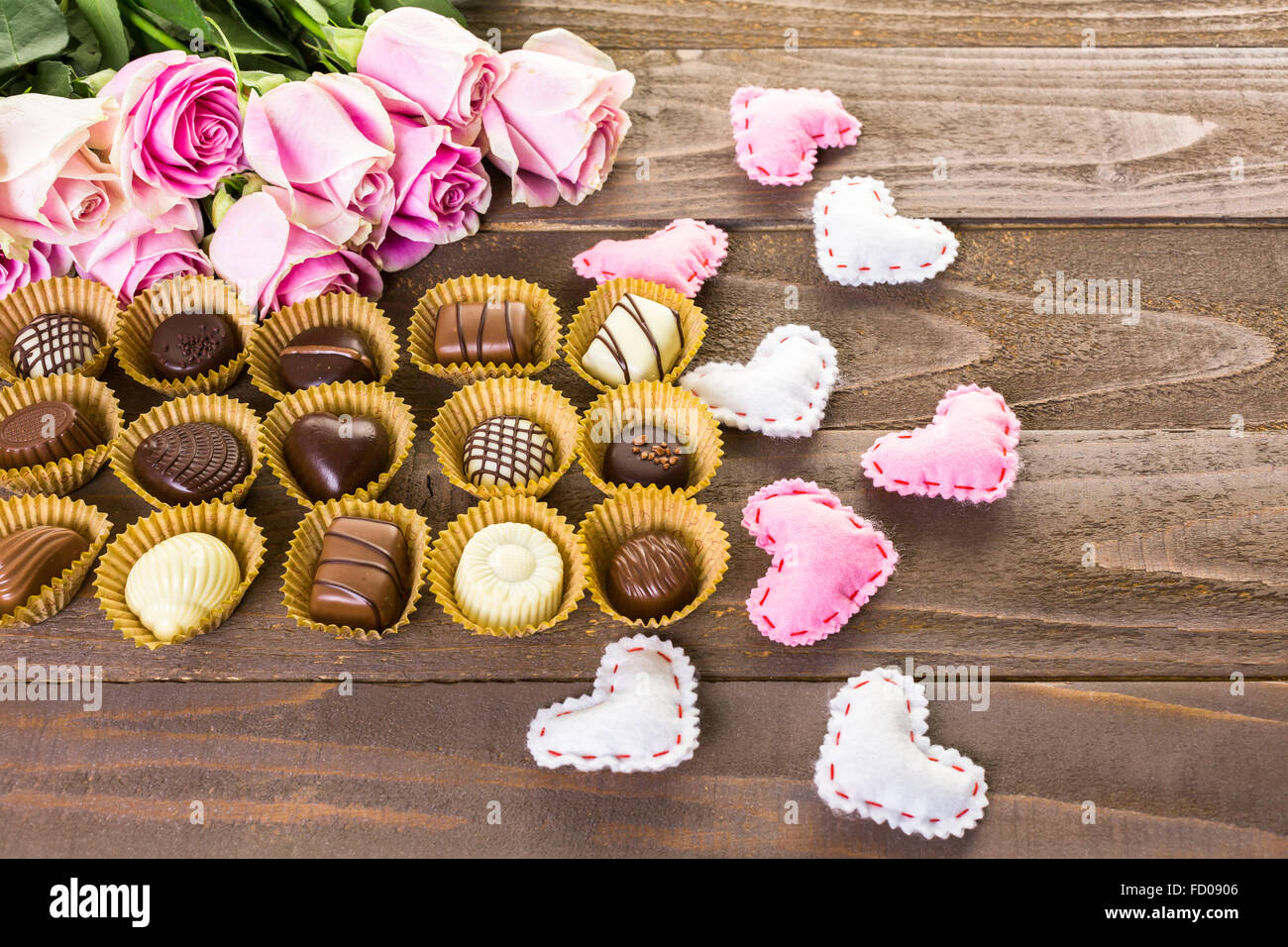Assorted chocolated with pink roses on wood table Stock Photo - Alamy