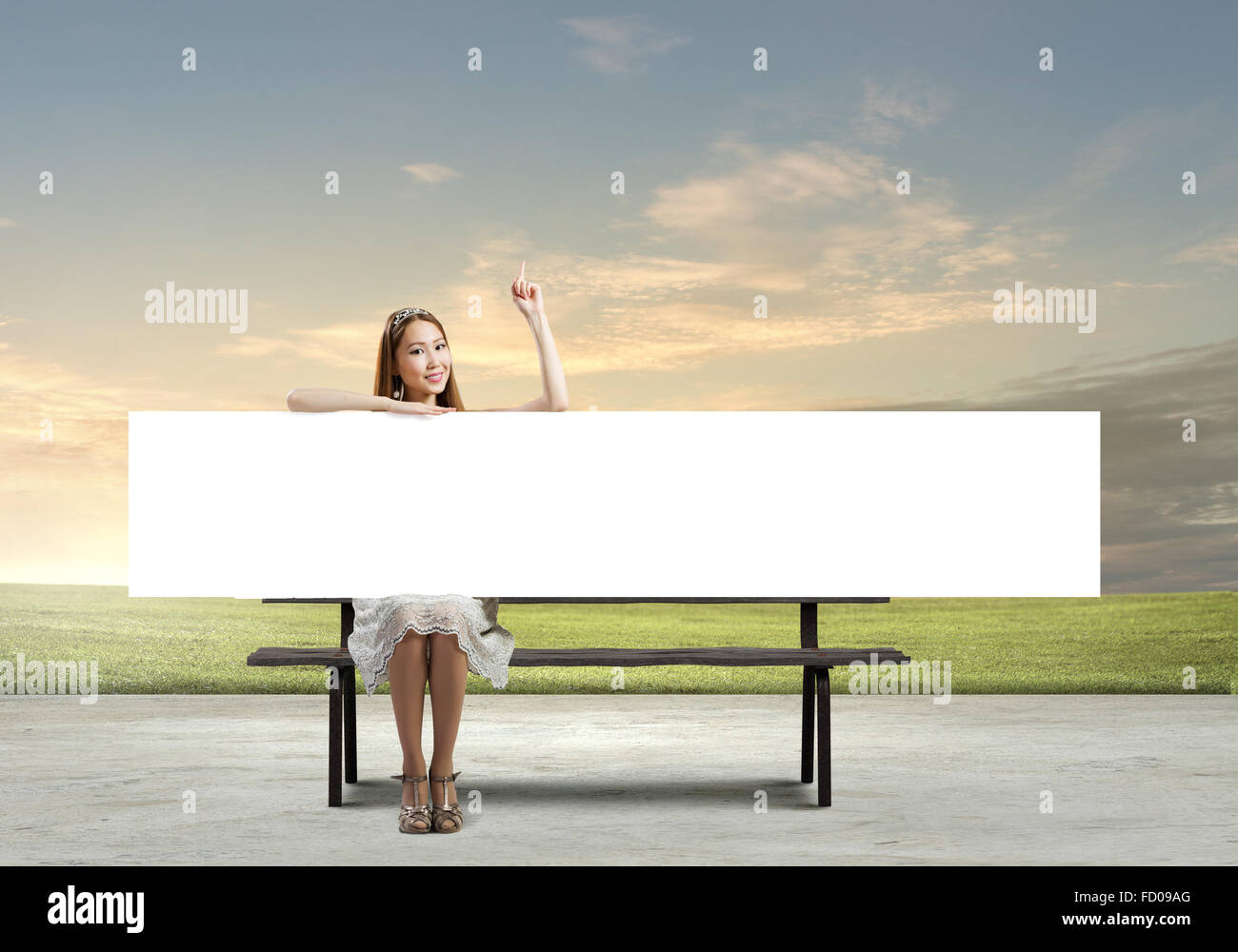 Young asian woman sitting on bench with blank banner Stock Photo - Alamy