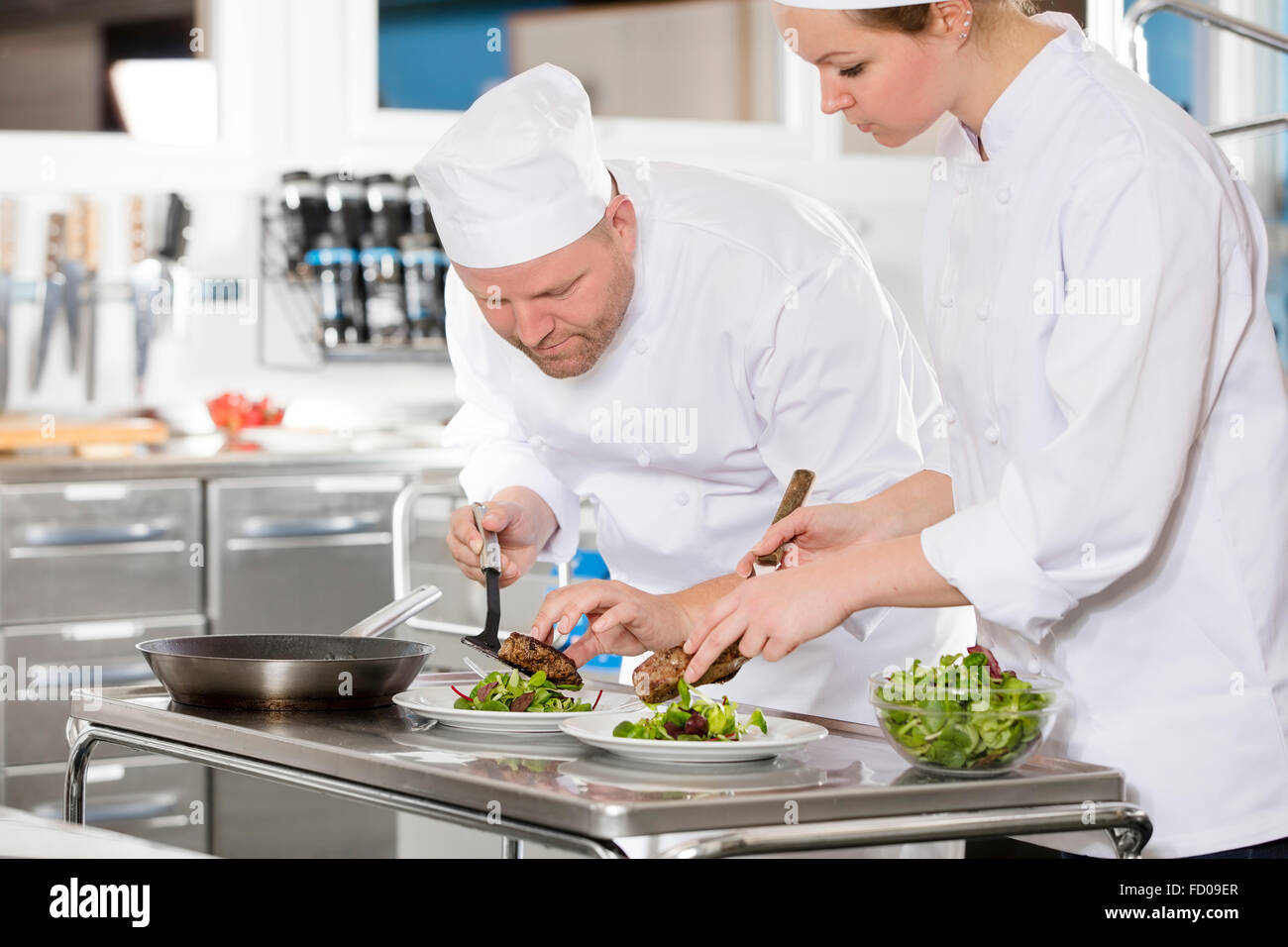 Professional chefs prepare steak dish at restaurant Stock Photo - Alamy