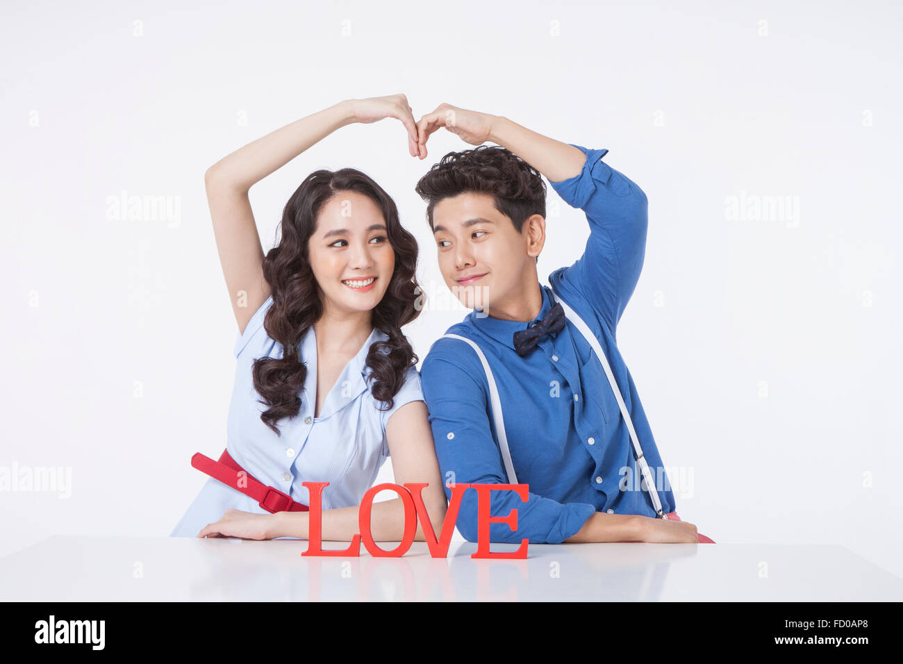 Young adult couple in retro style seated at table with solid word LOVE ...