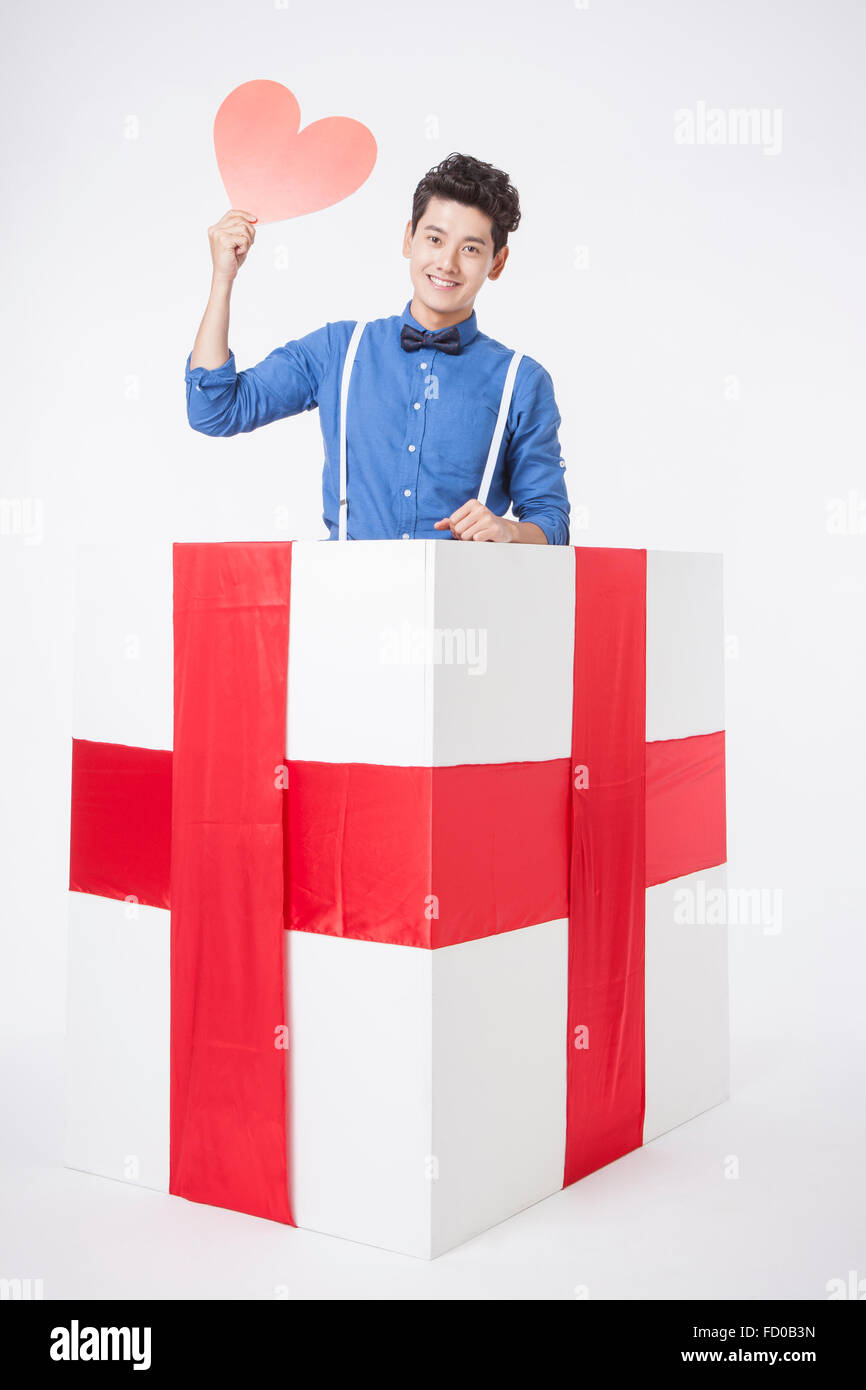 Man in blue shirt placed in a gift box staring forward and holding a ...