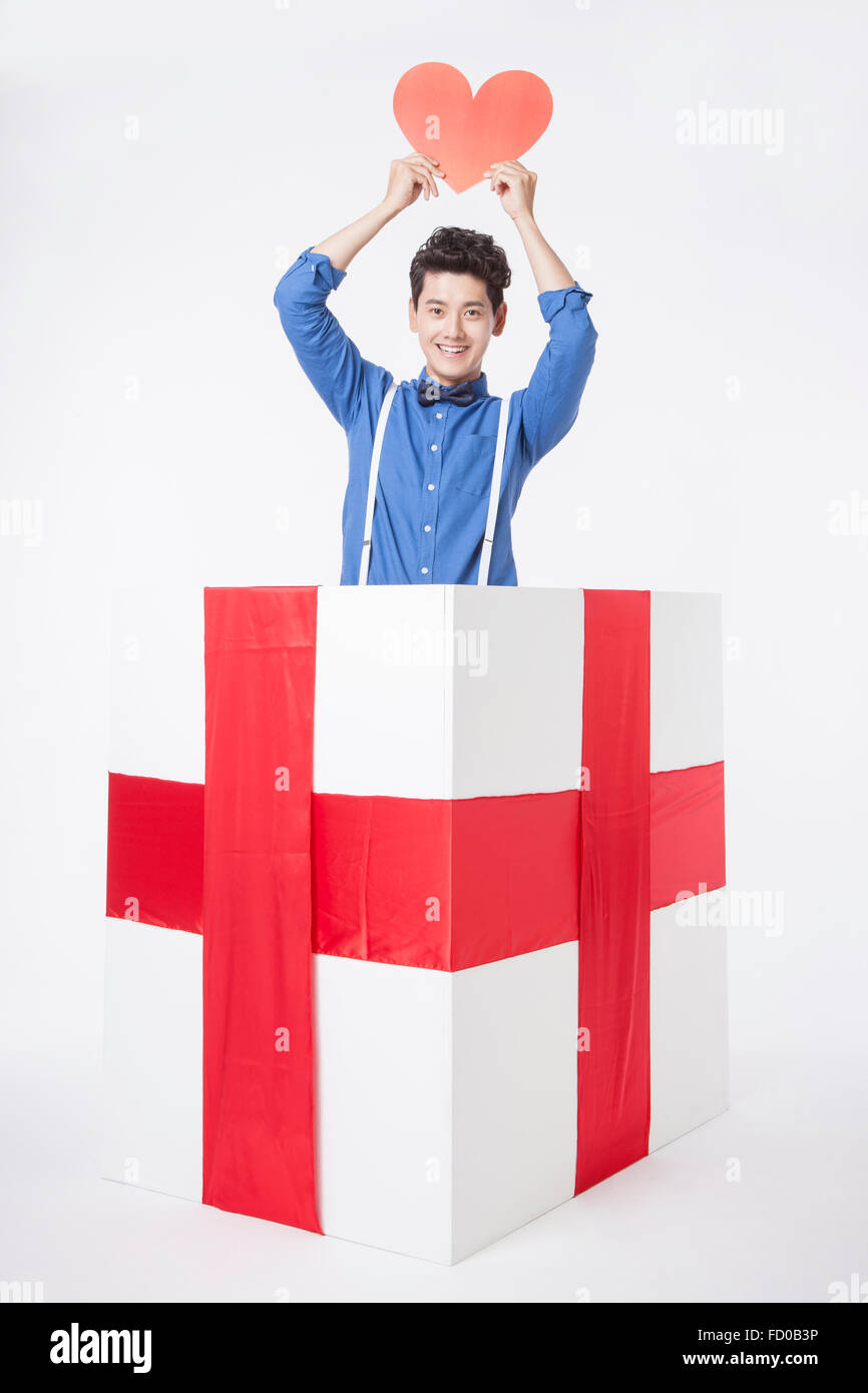 Man in blue shirt placed in a gift box staring forward and holding a ...