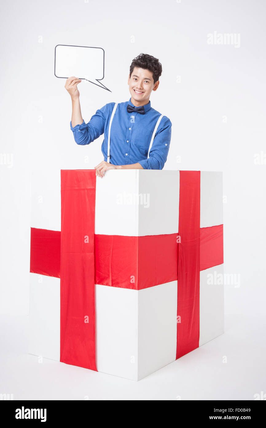 Man in blue shirt placed in a gift box staring forward and holding a ...
