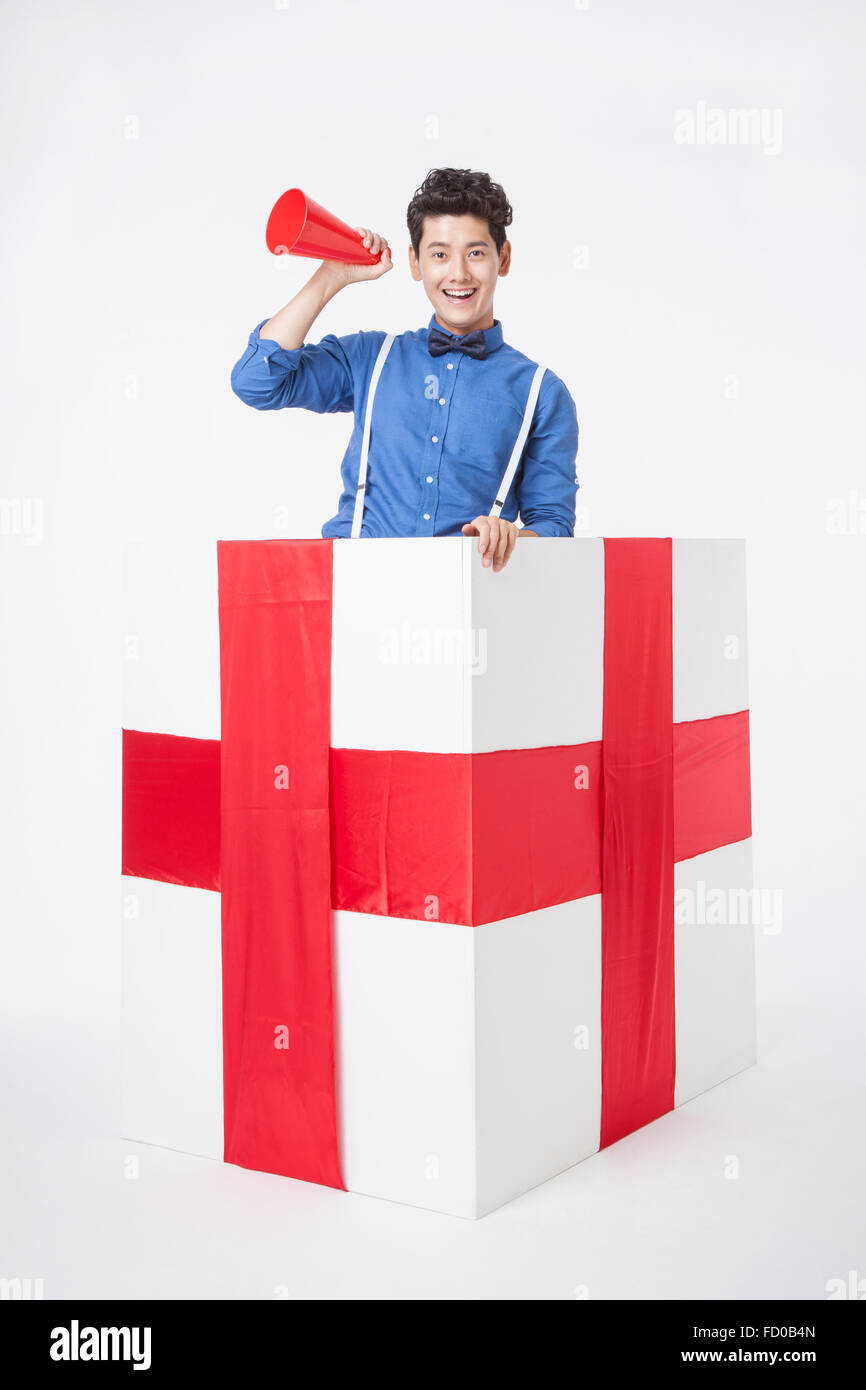Man in blue shirt placed in a gift box staring forward and holding a ...
